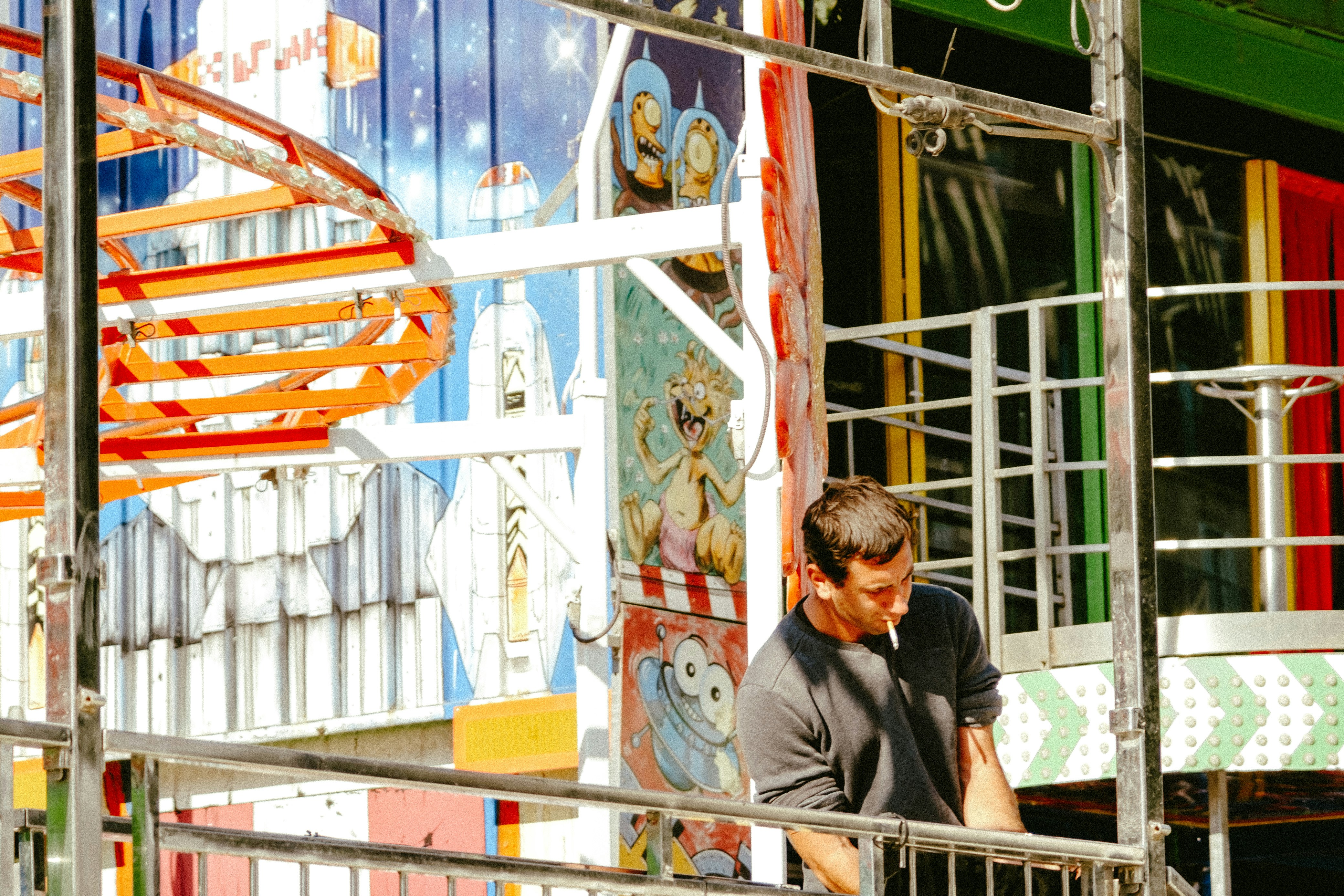 man in black crew neck t-shirt standing beside white metal fence during daytime