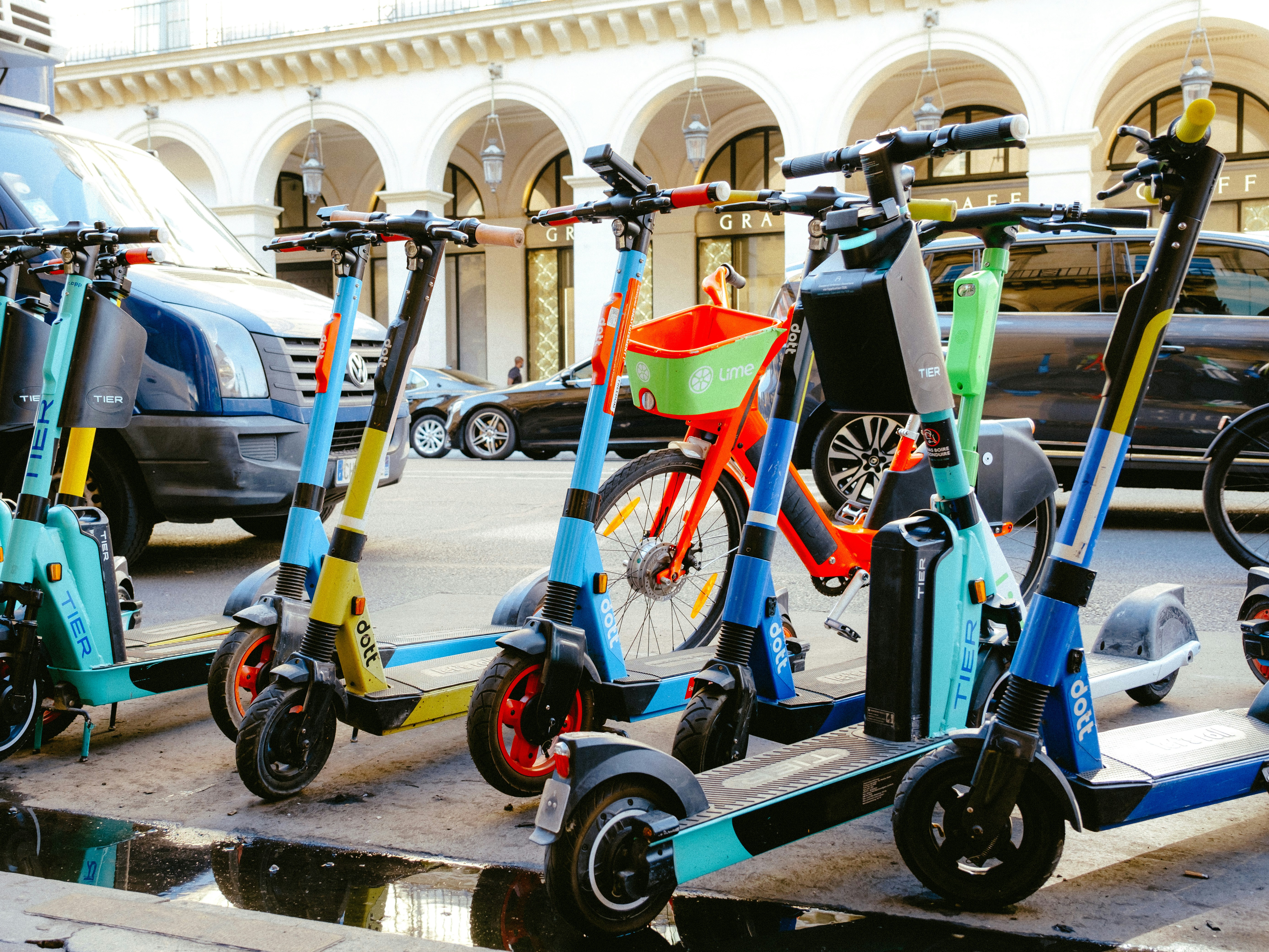 A row of vibrant electric scooters parked along a city street, showcasing modern urban transportation options.