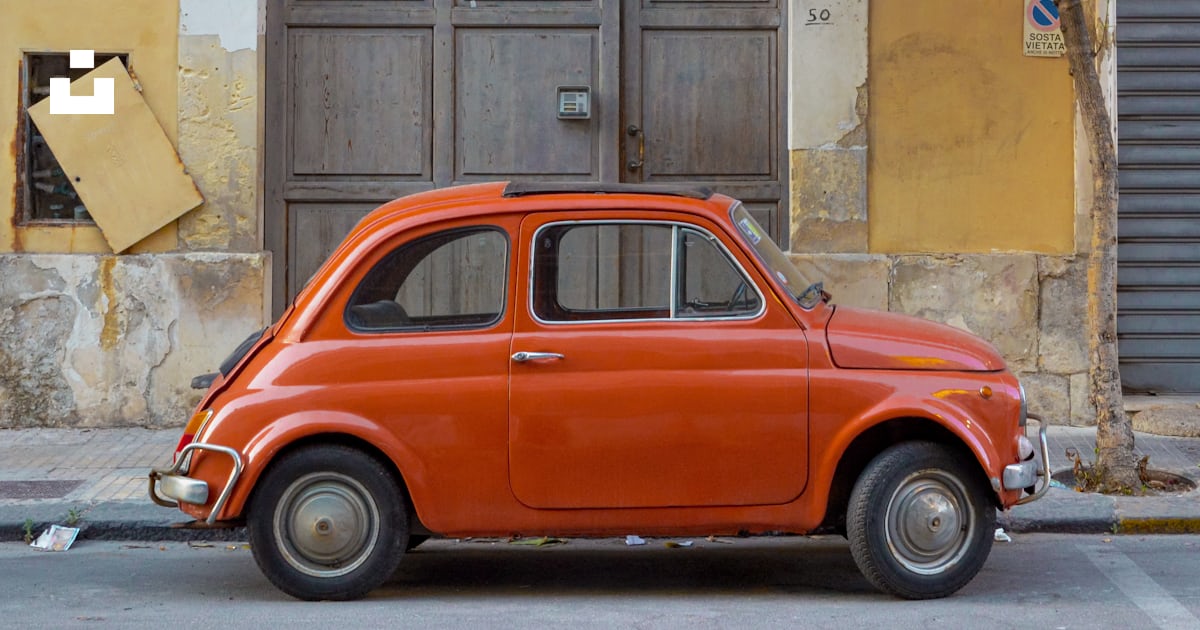 Red Volkswagen Beetle Parked Beside Brown Concrete Building During