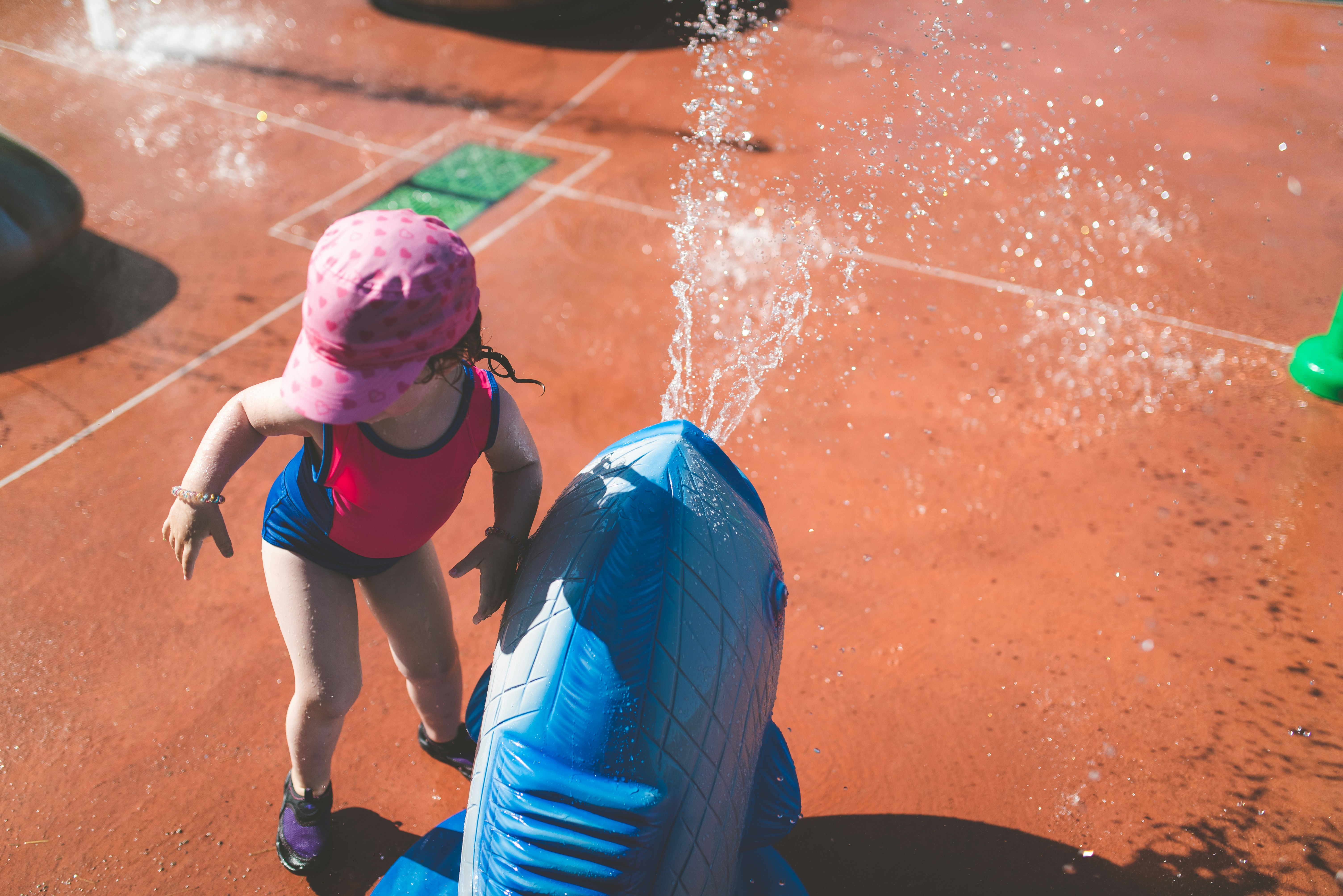 Girl in pink tank top and blue shorts sitting on blue inflatable ring ...