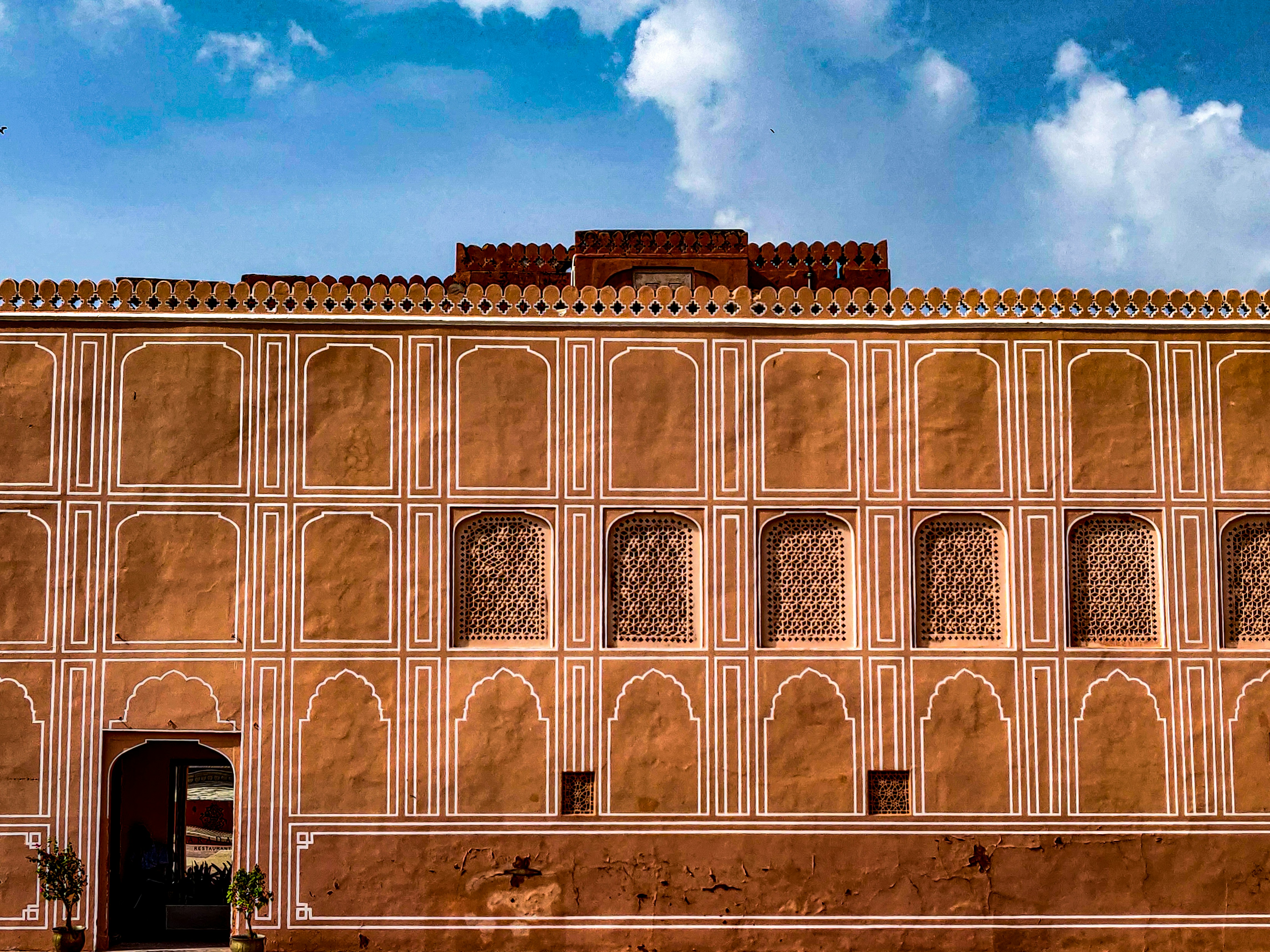 Ornate facade of City Palace in Jaipur with intricate patterns against a clear blue sky.