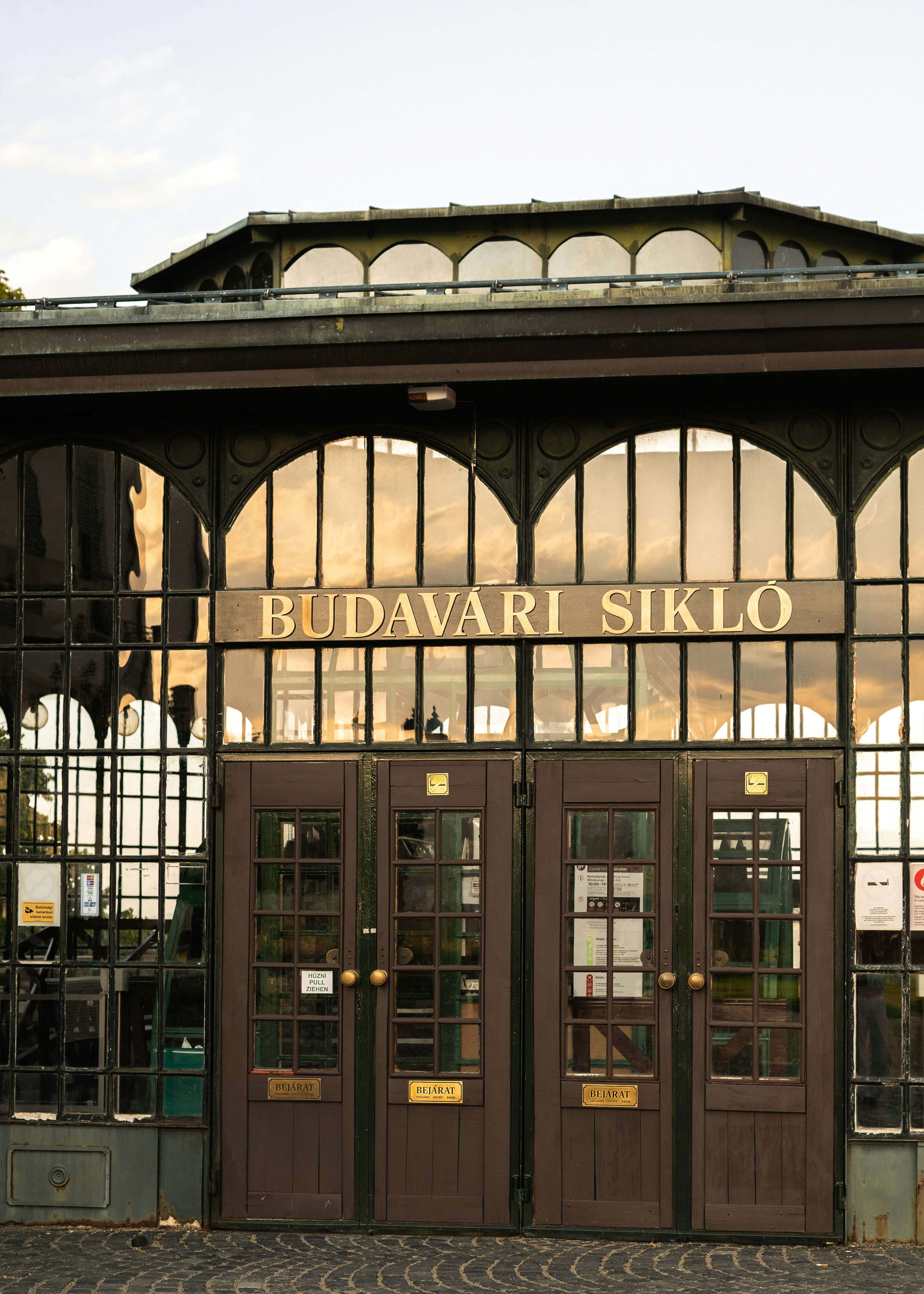 Budavári Sikló Gateway: Arched Glass and Warm Facade Reflections