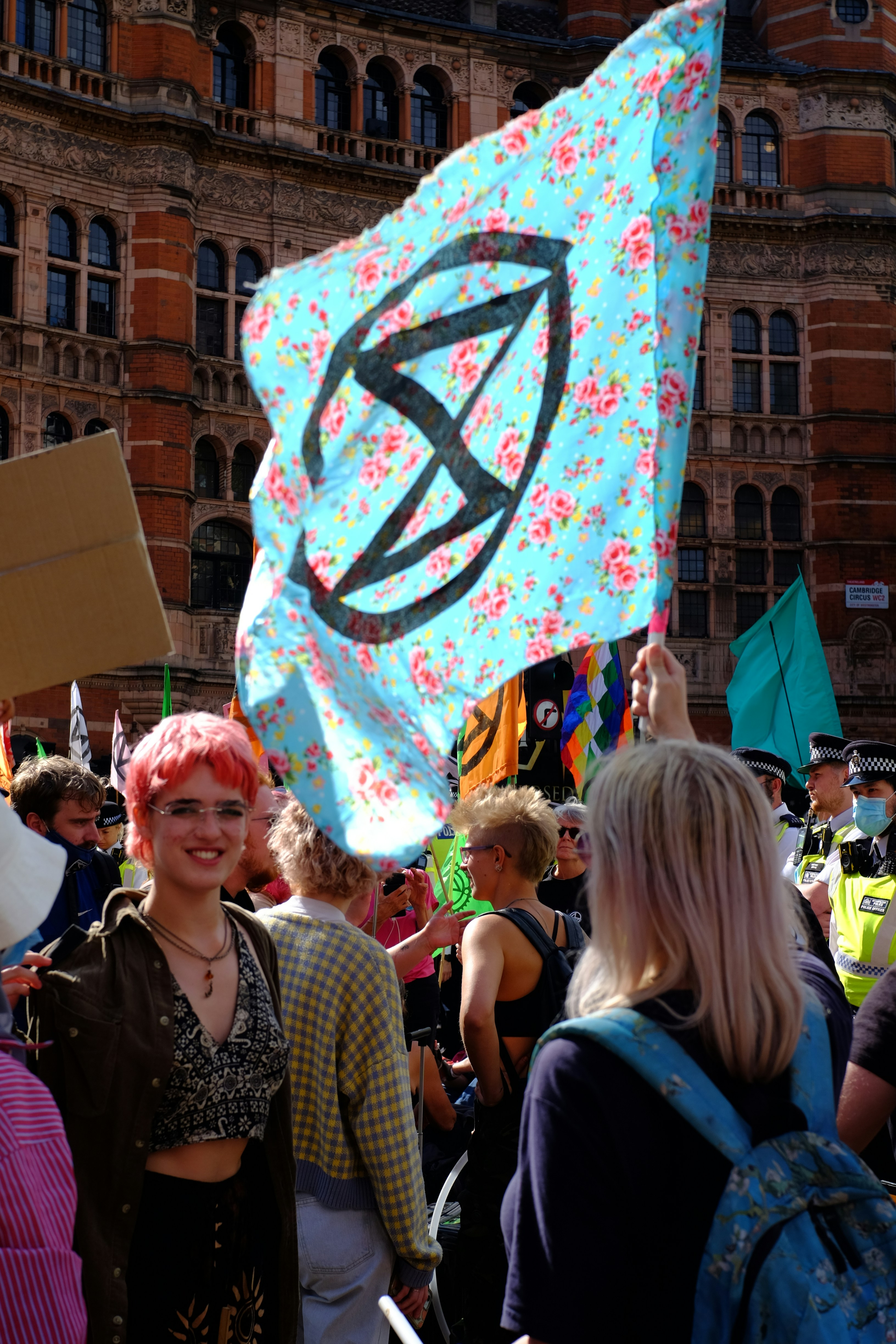 Blue Floral Flag Cuts Through the Crowd Before Brick Facades