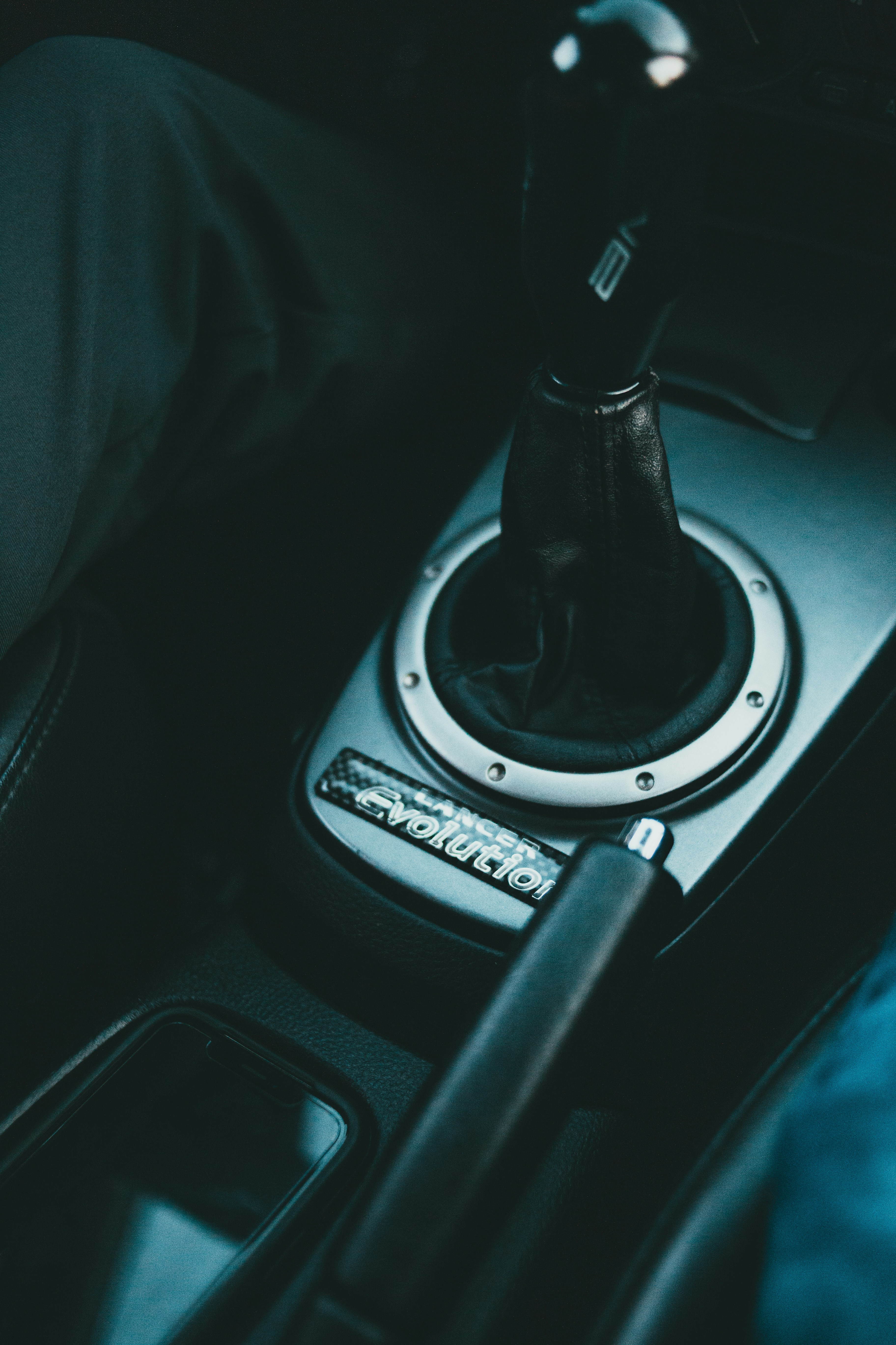 Close-up of a gear shift lever and console in a performance vehicle, showcasing the 'Evolution' branding. The sleek design emphasizes the car's sporty aesthetic.