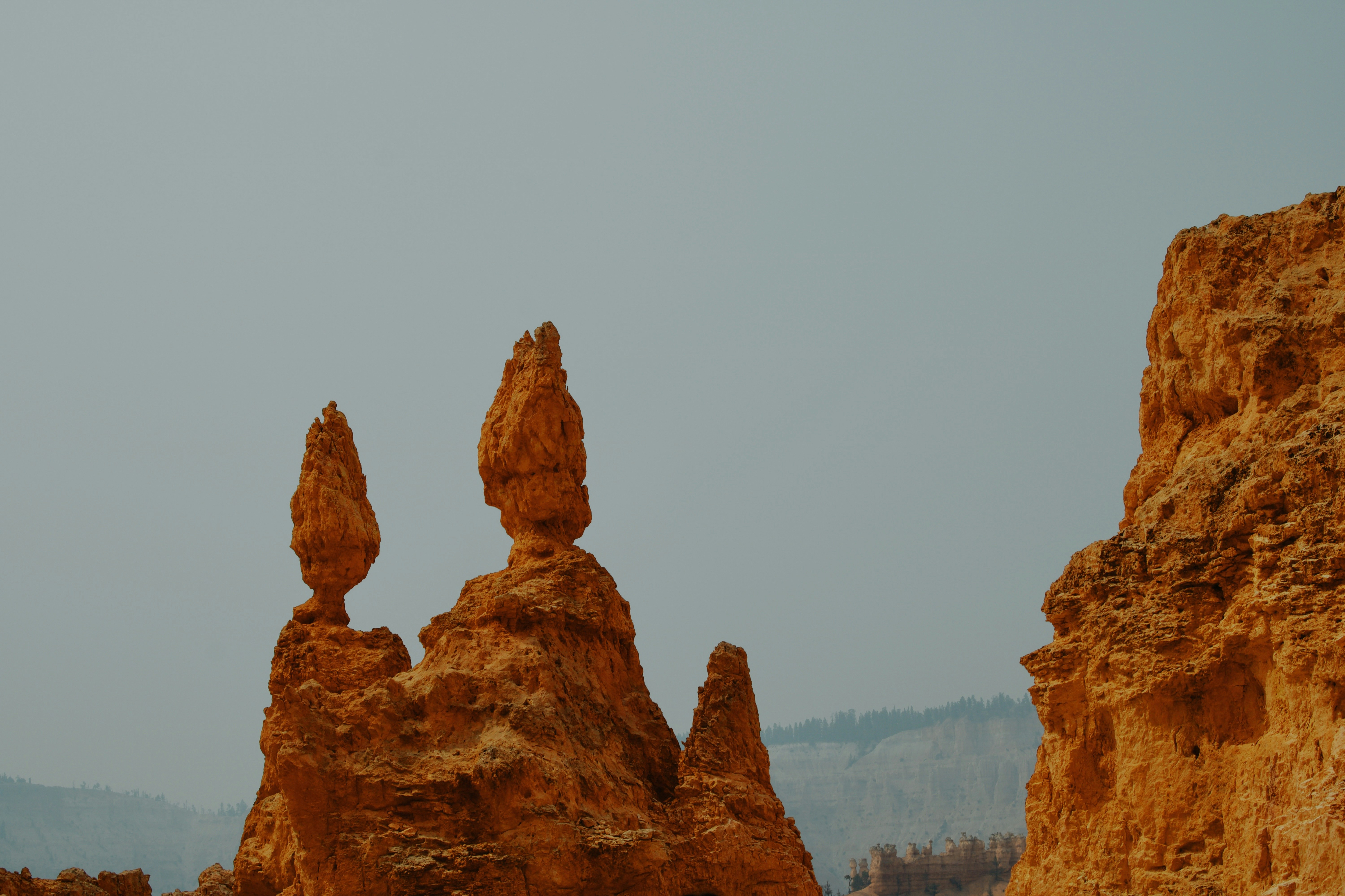 Rock formations with unique spires against a hazy sky in a desert landscape.
