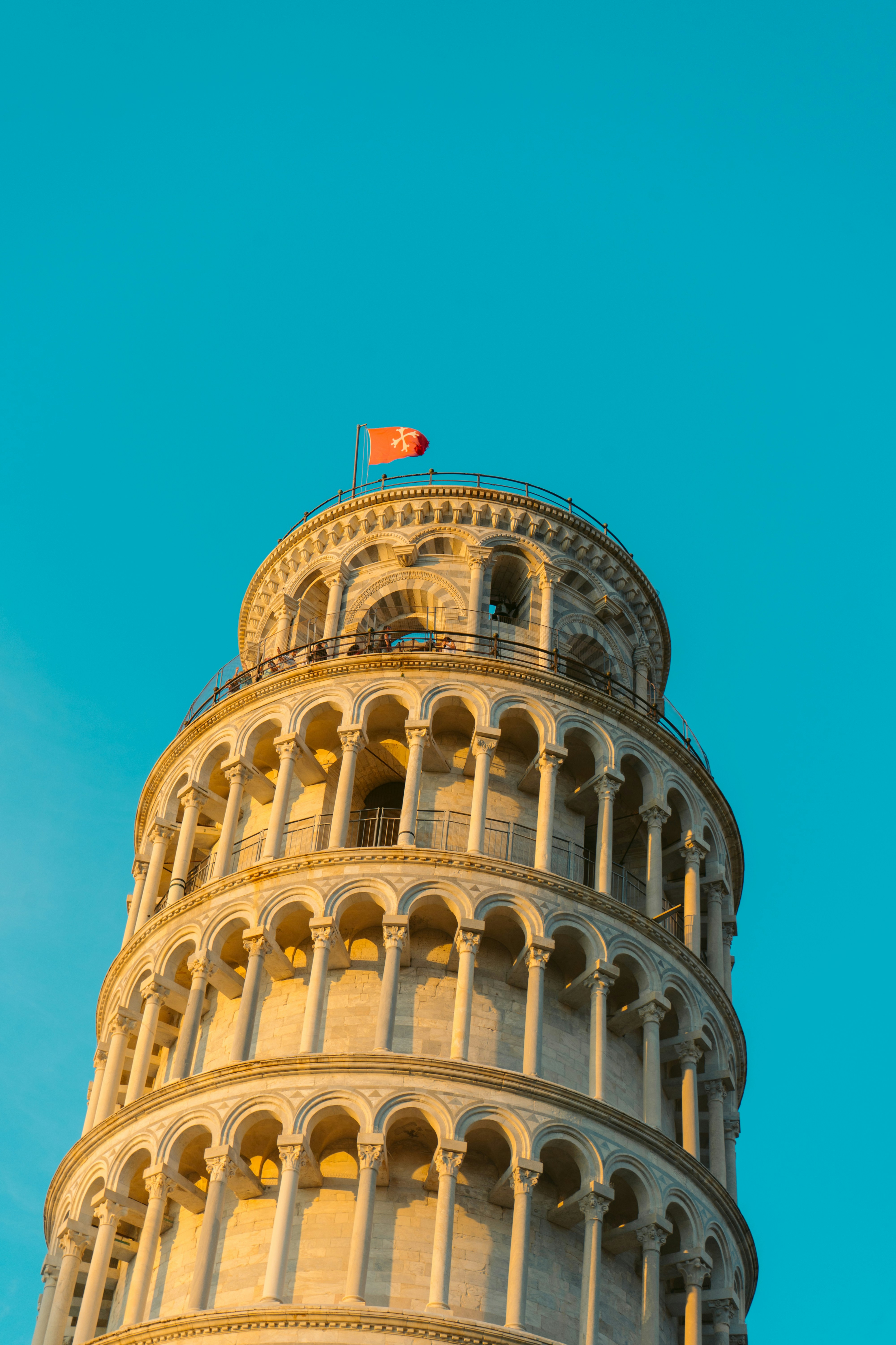 Flag-Topped Pisa: Sunlit Arcades Against a Cerulean Sky