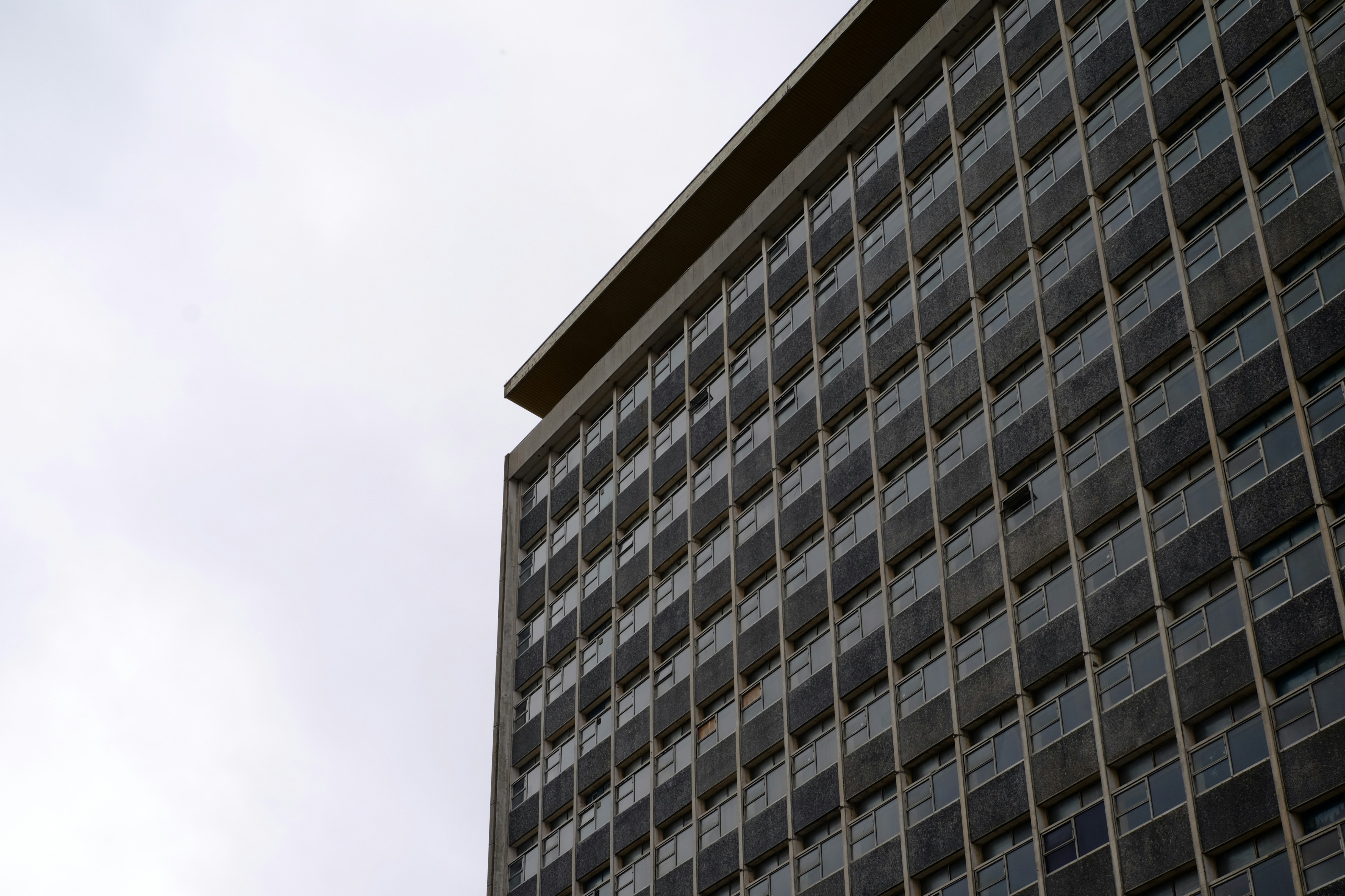 High-rise building with a repetitive grid pattern under a cloudy sky.