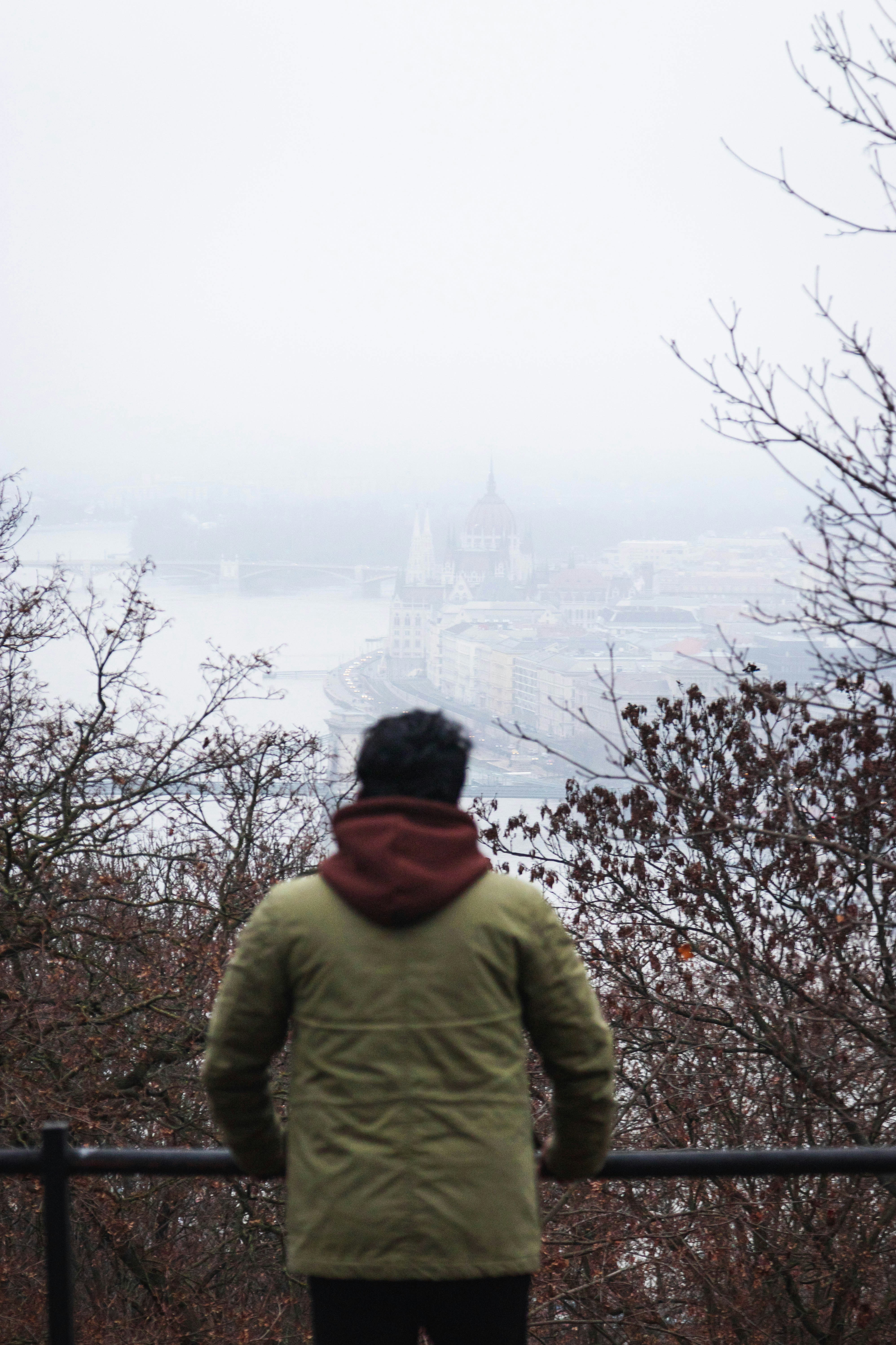 Edge of the Fog: A solitary watcher surveys a river-city veiled in mist.