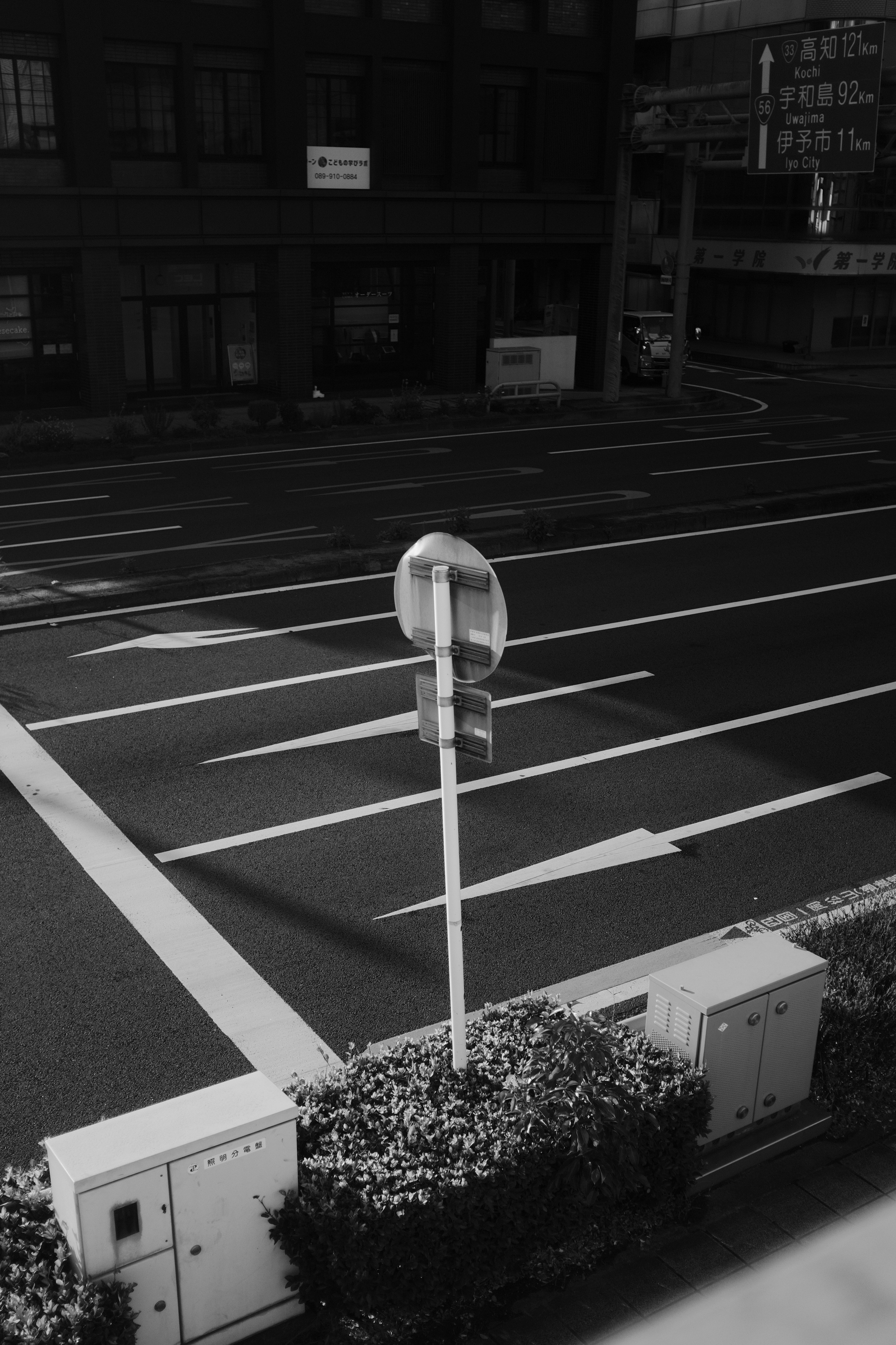 Monochrome Sentinel: The Circular Sign Anchoring a Quiet Urban Crossing