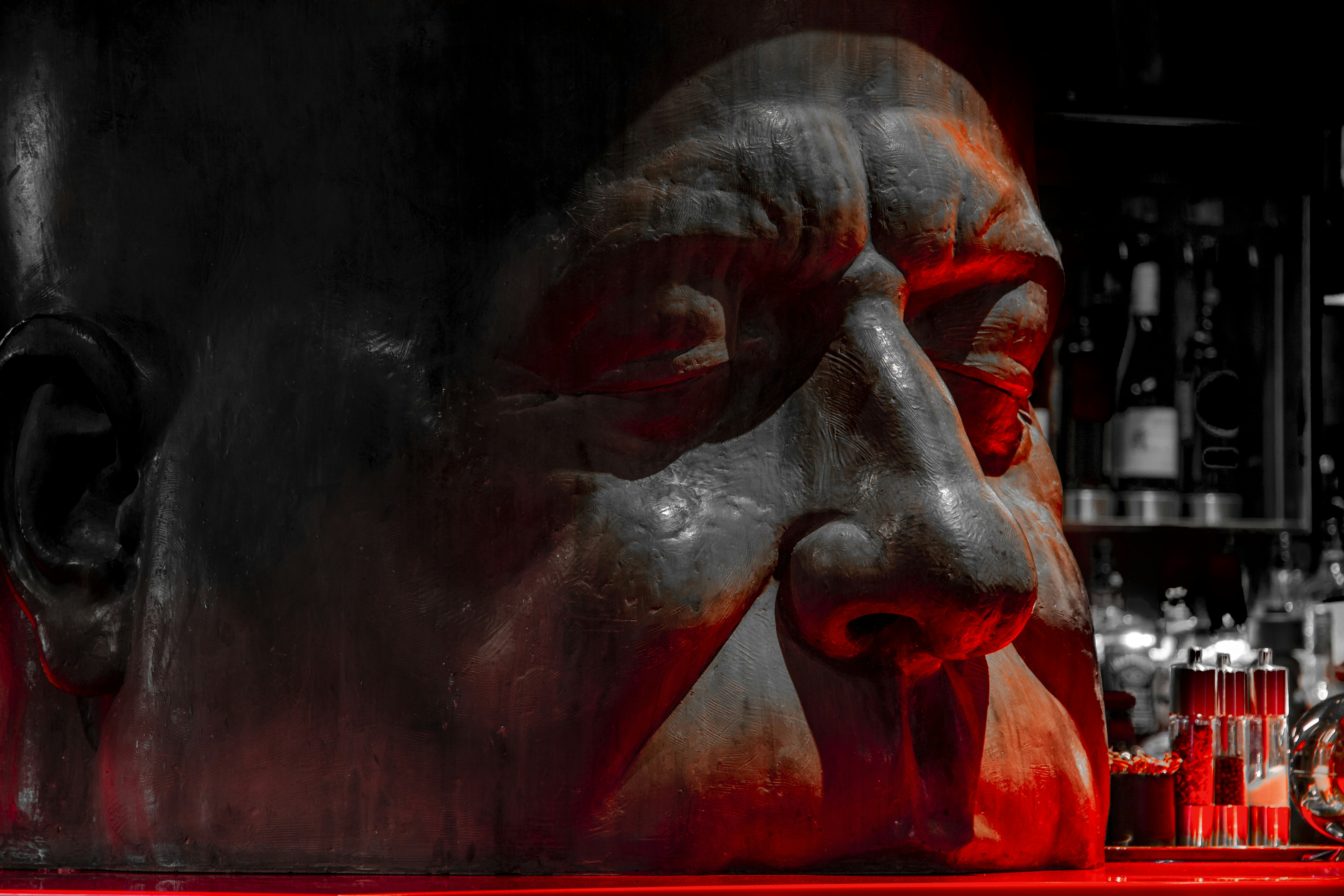 Crimson Quiet at the Bar: Close-Up of a Resting Head Beneath Neon Bottles