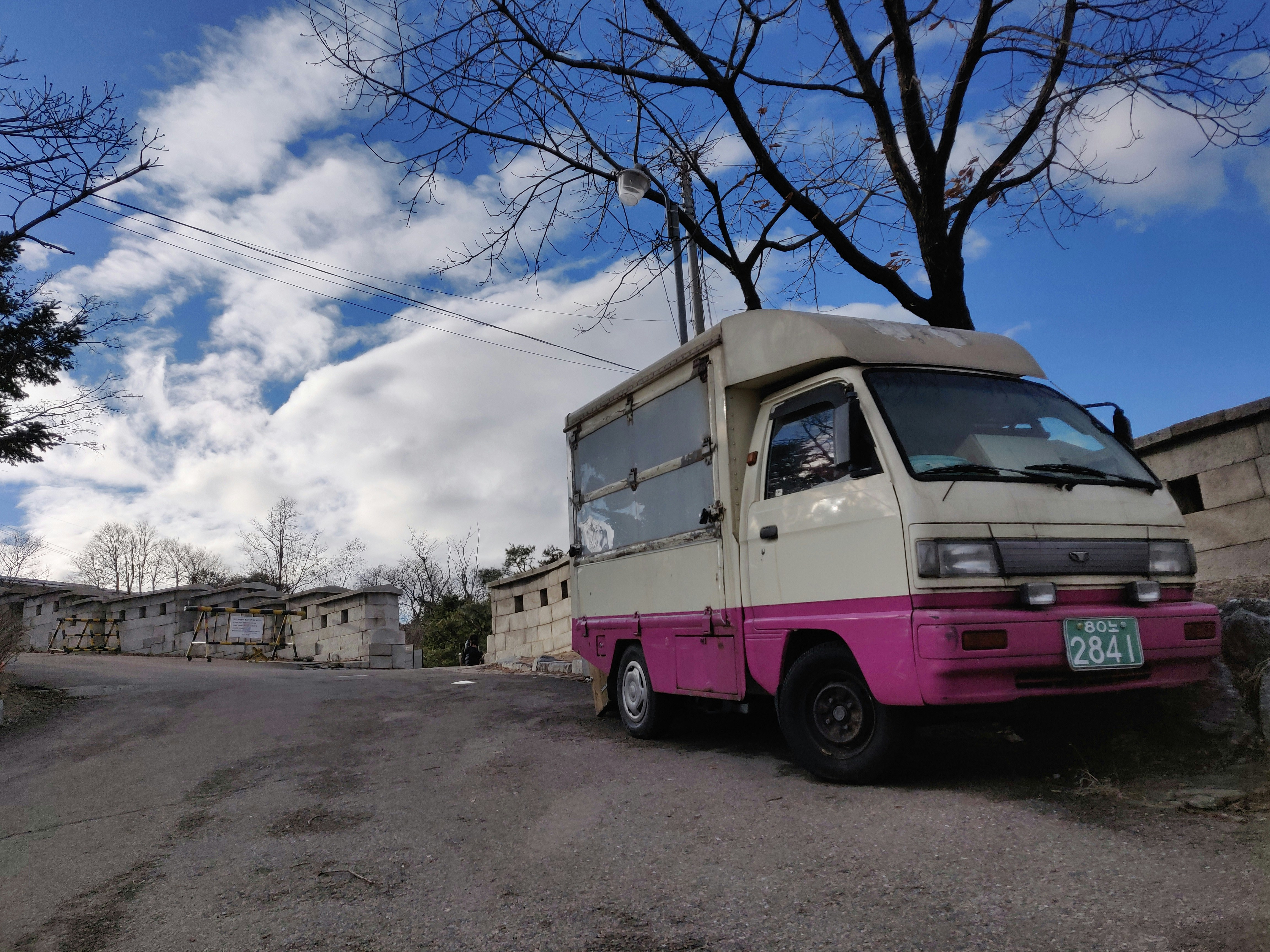 Pink-Top Microvan on an Empty Street Beneath a Sky Strung with Clouds