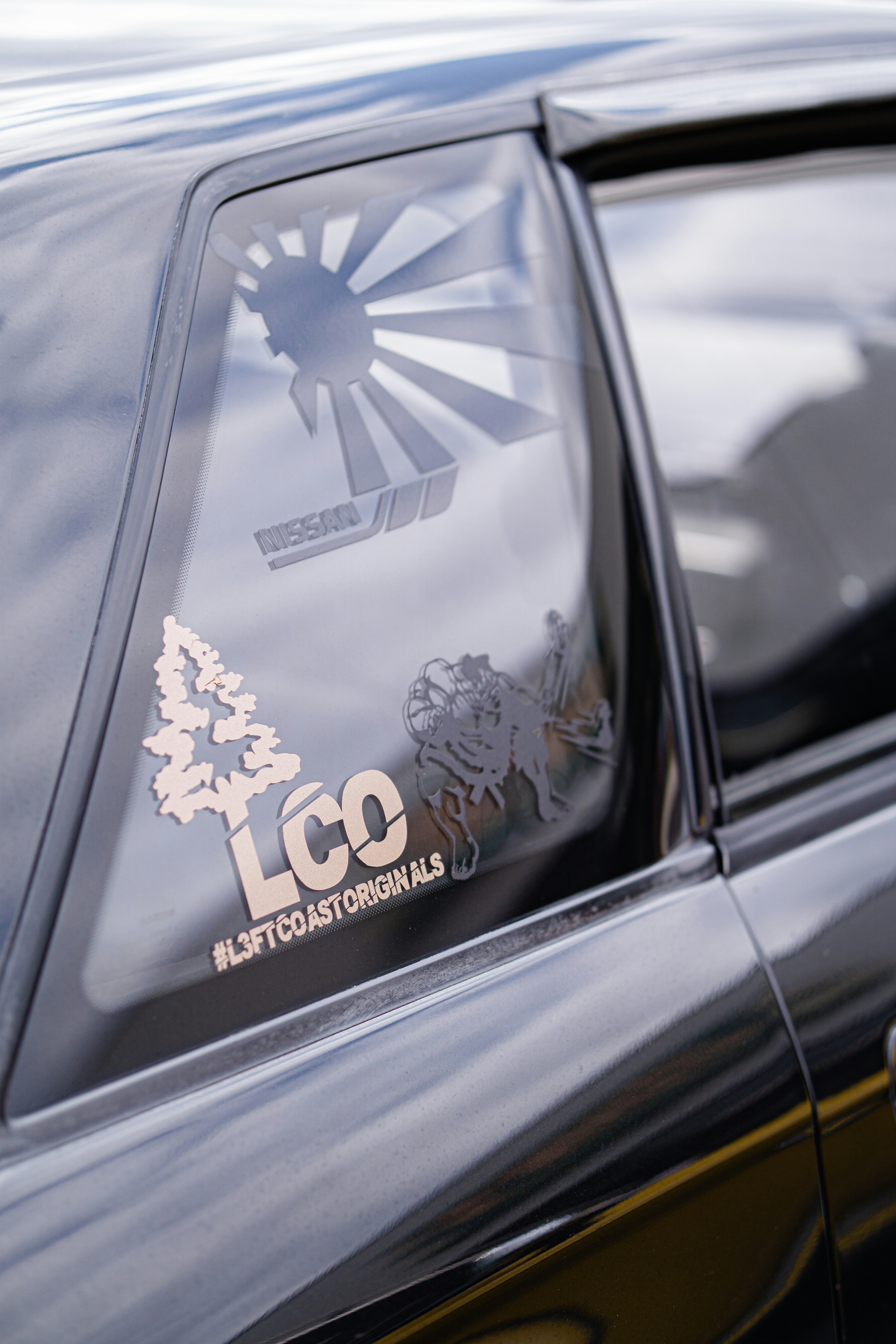 Sunburst Emblem Meets LCO Sticker on a Glossy Car Window