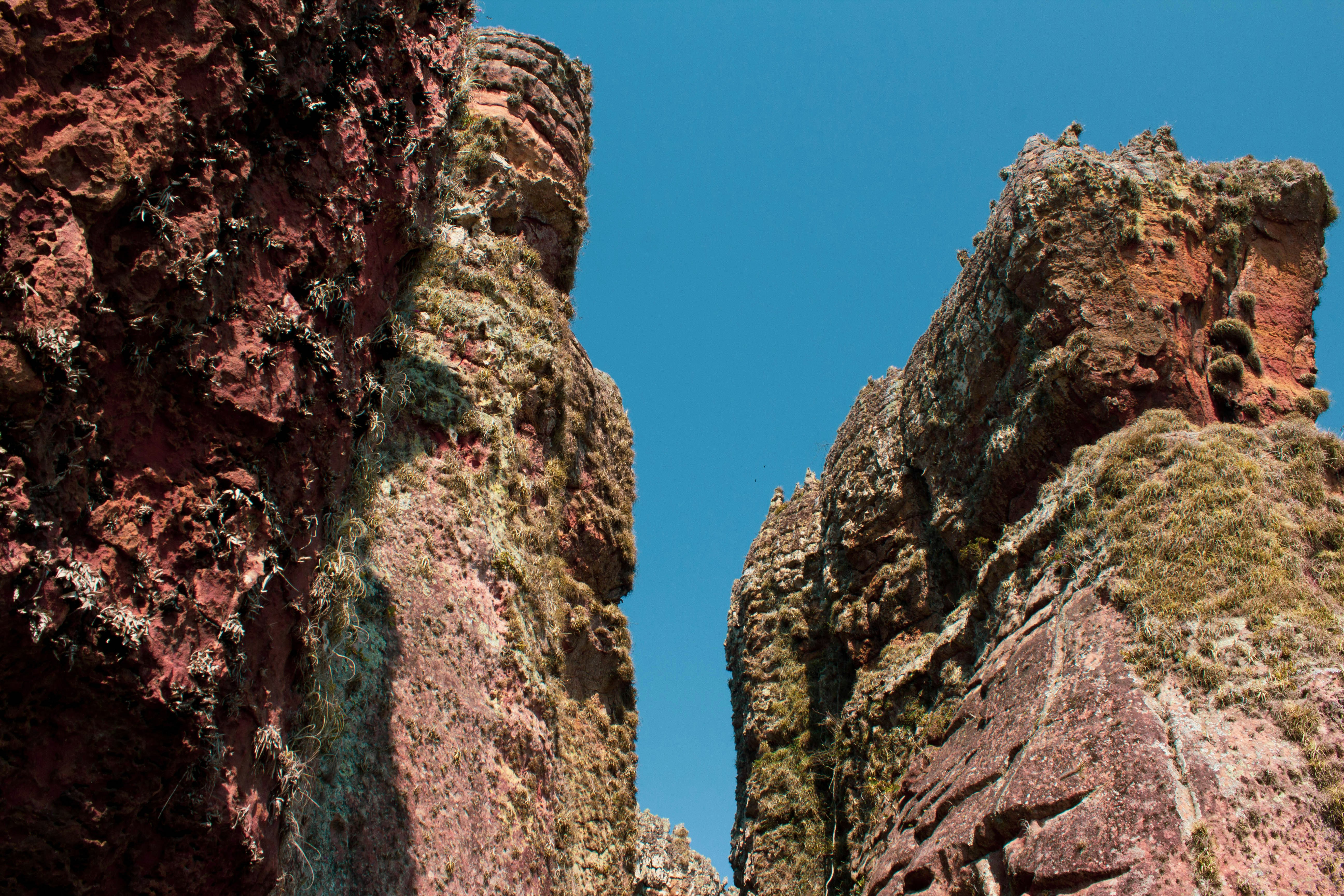 Two towering rock formations framed against a clear blue sky, showcasing vibrant textures and colors of the natural landscape.