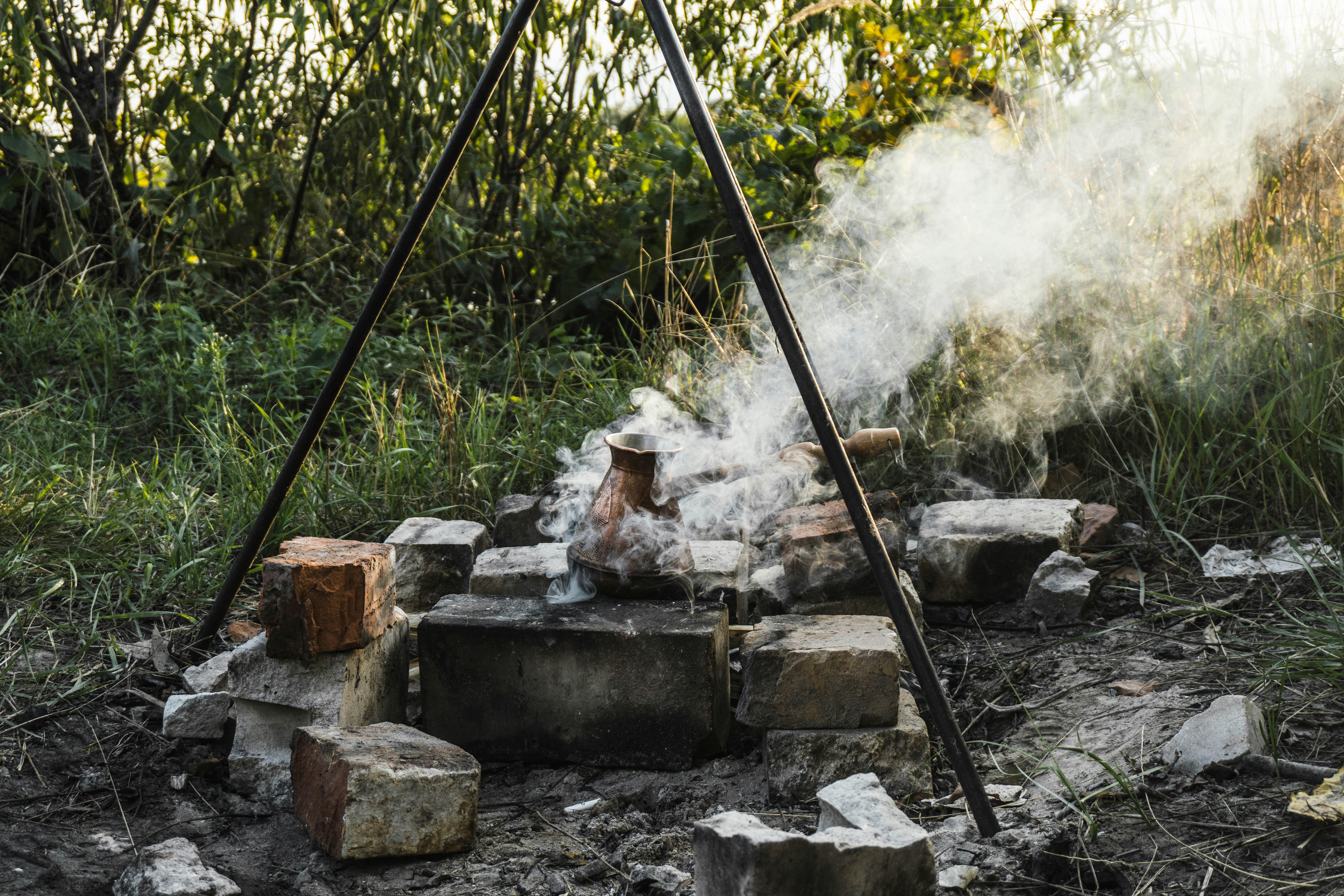 Three-Legged Cooking Ritual: Smoke Rises Over a Rustic Stone Hearth