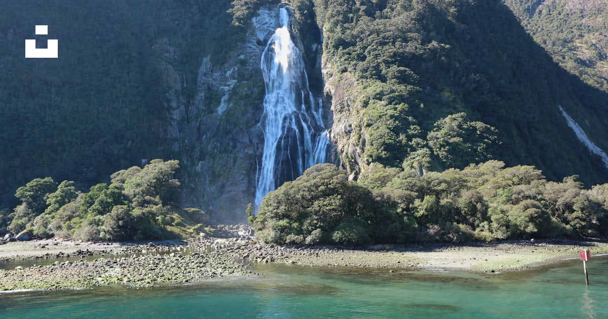 昼間の緑の木々と山の真ん中にある滝の写真 Unsplashで見つけるニュージーランドの無料写真