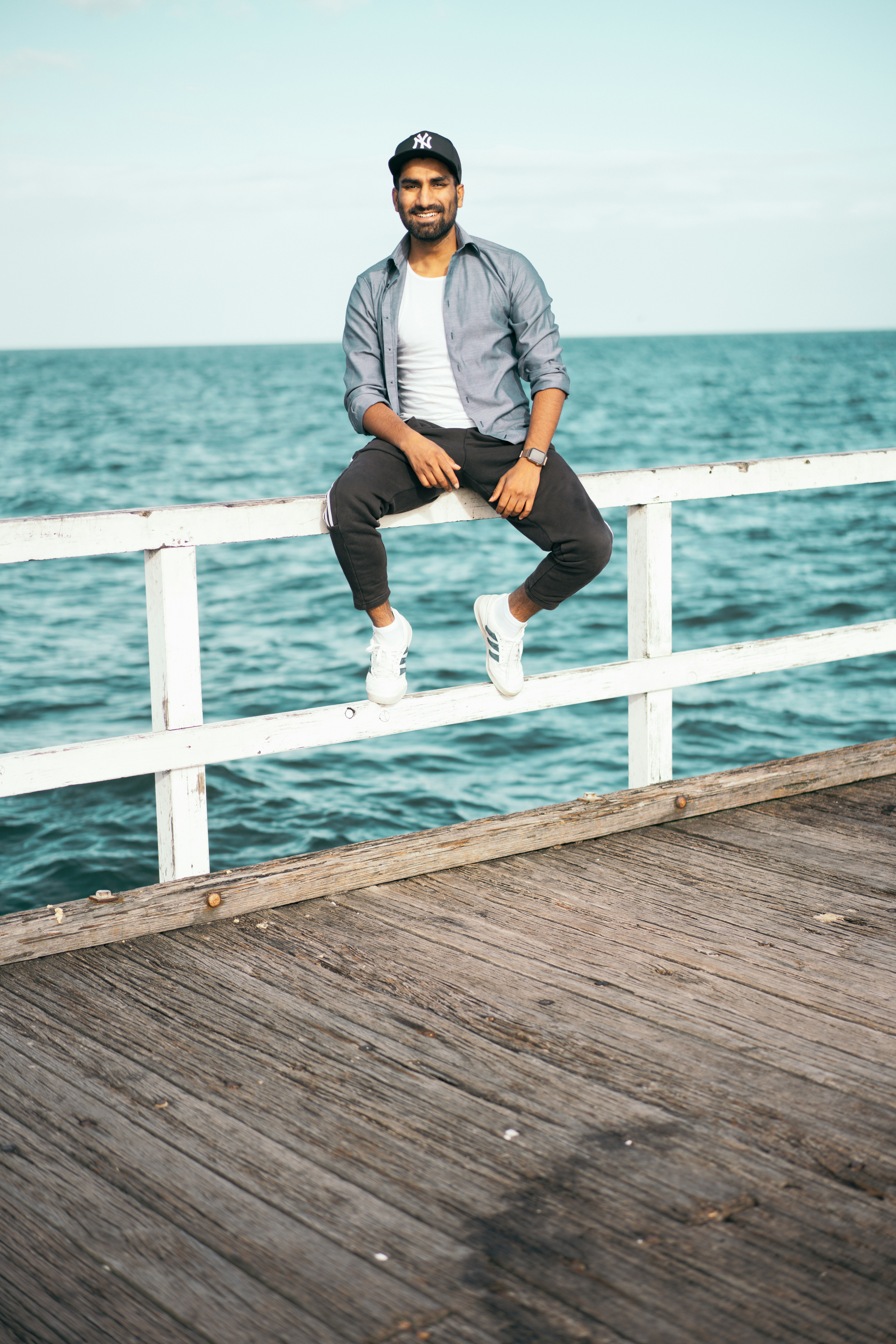 man in gray long sleeve shirt and brown pants sitting on wooden dock during daytime