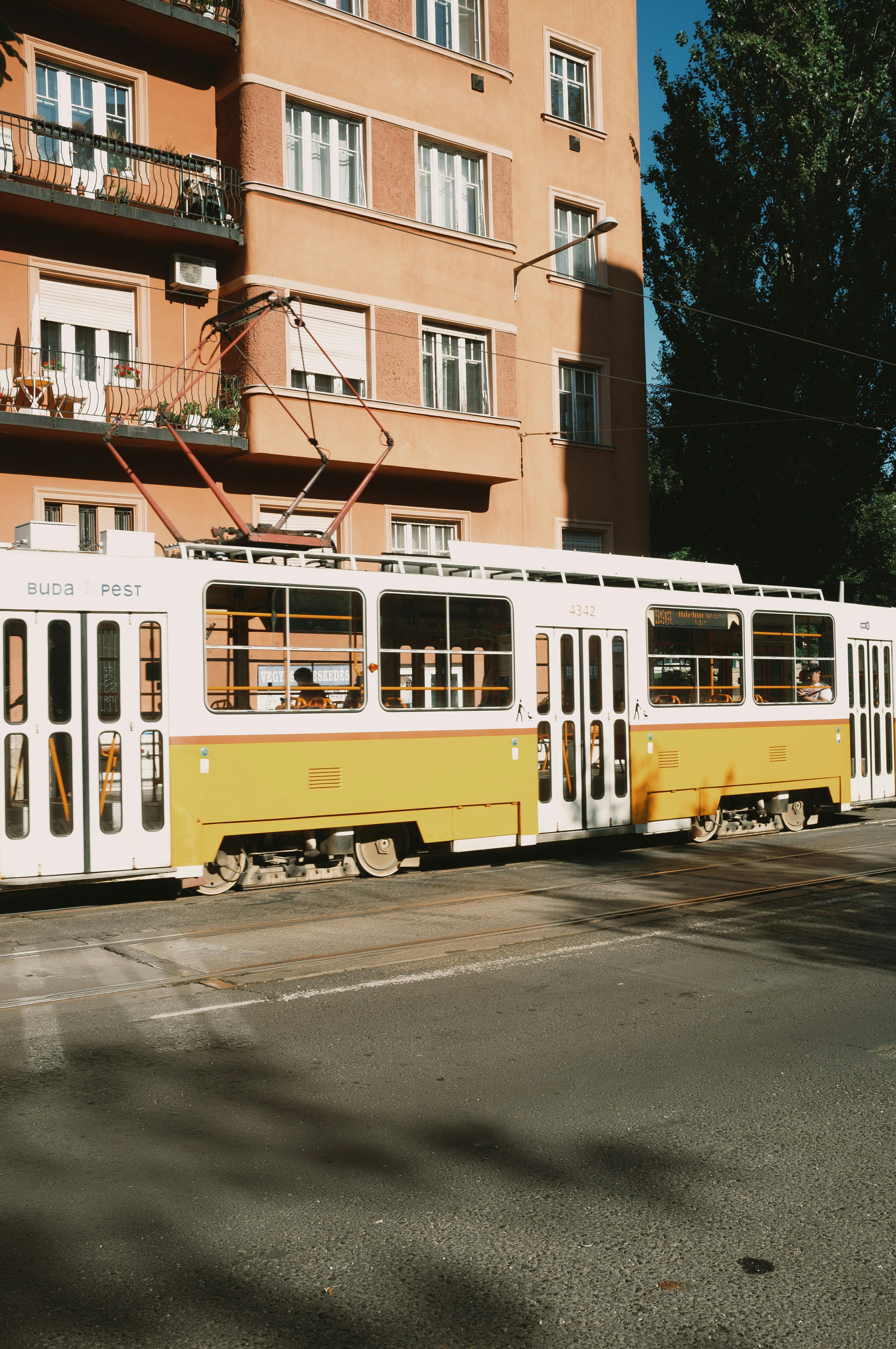 Sun-Kissed Tram Sliding Past a Peach-Colored Facade
