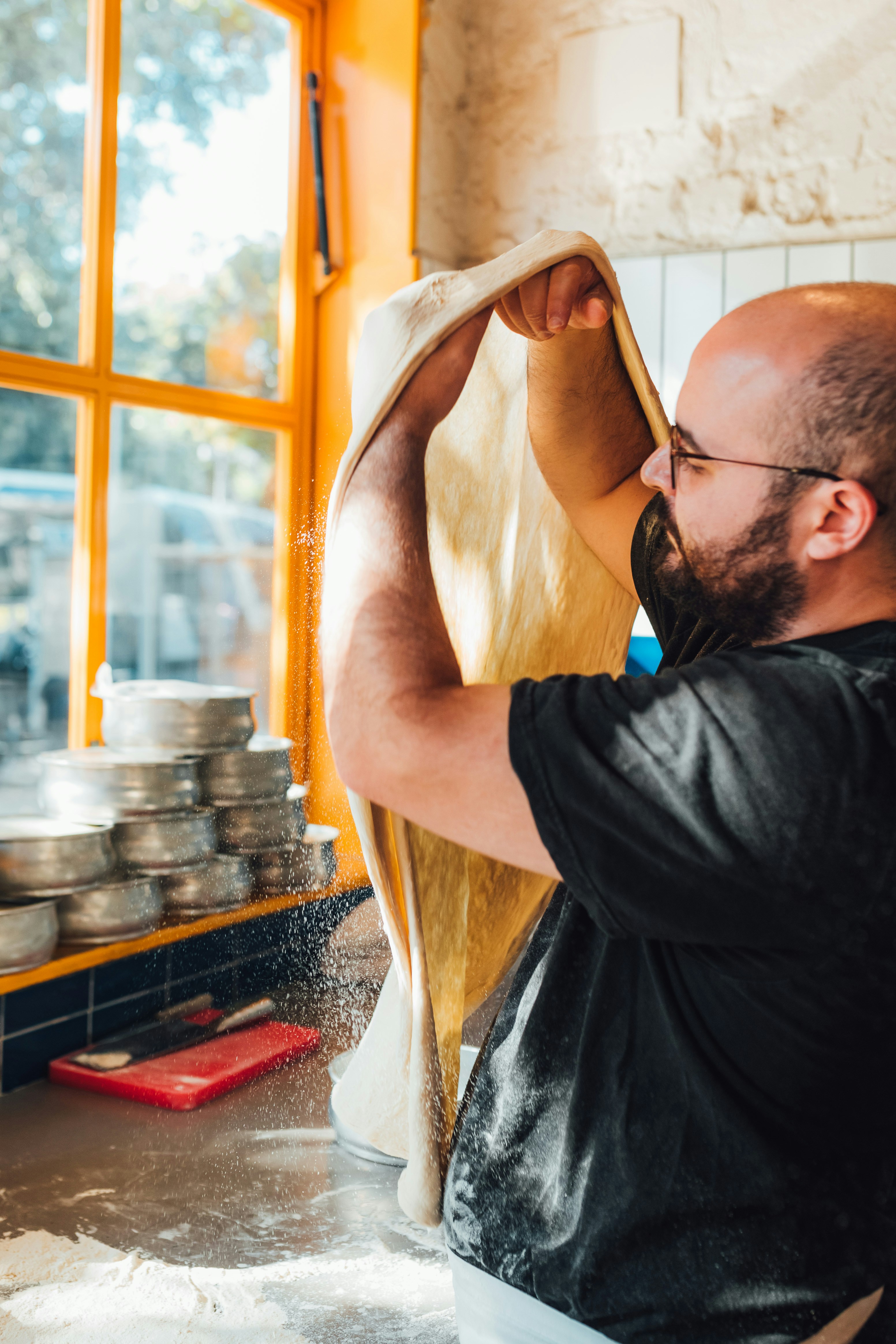 Throwing Dough in Focus: A Hand-Pressed Moment in a Busy Kitchen