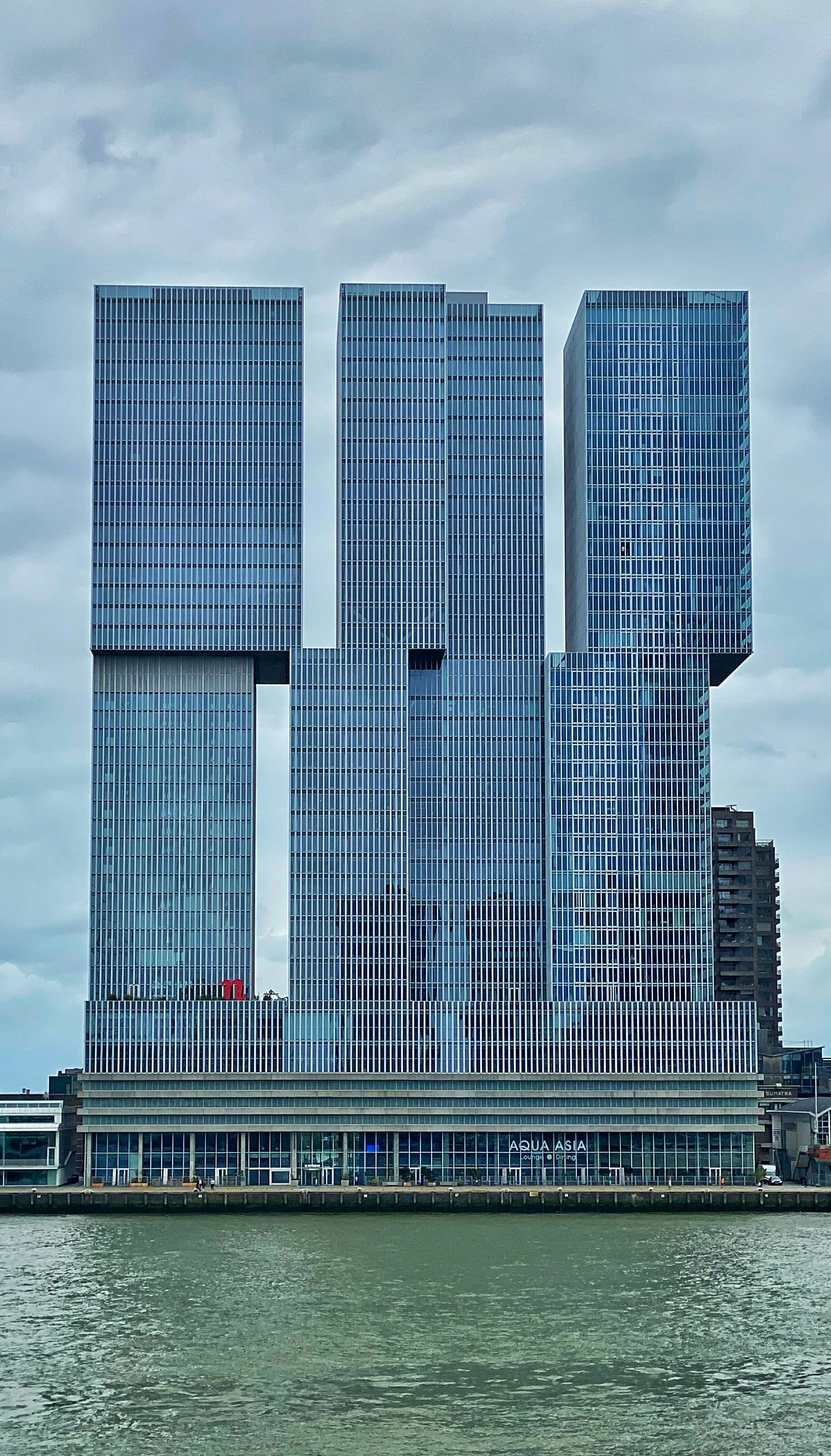 A cluster of sleek, modern skyscrapers reflecting the cloudy sky, showcasing a blend of glass and steel design elements.