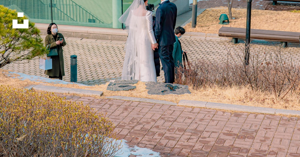 낮 동안 보도를 걷고 있는 하얀 웨딩 드레스를 입은 여자 사진 Unsplash의 무료 부부 이미지