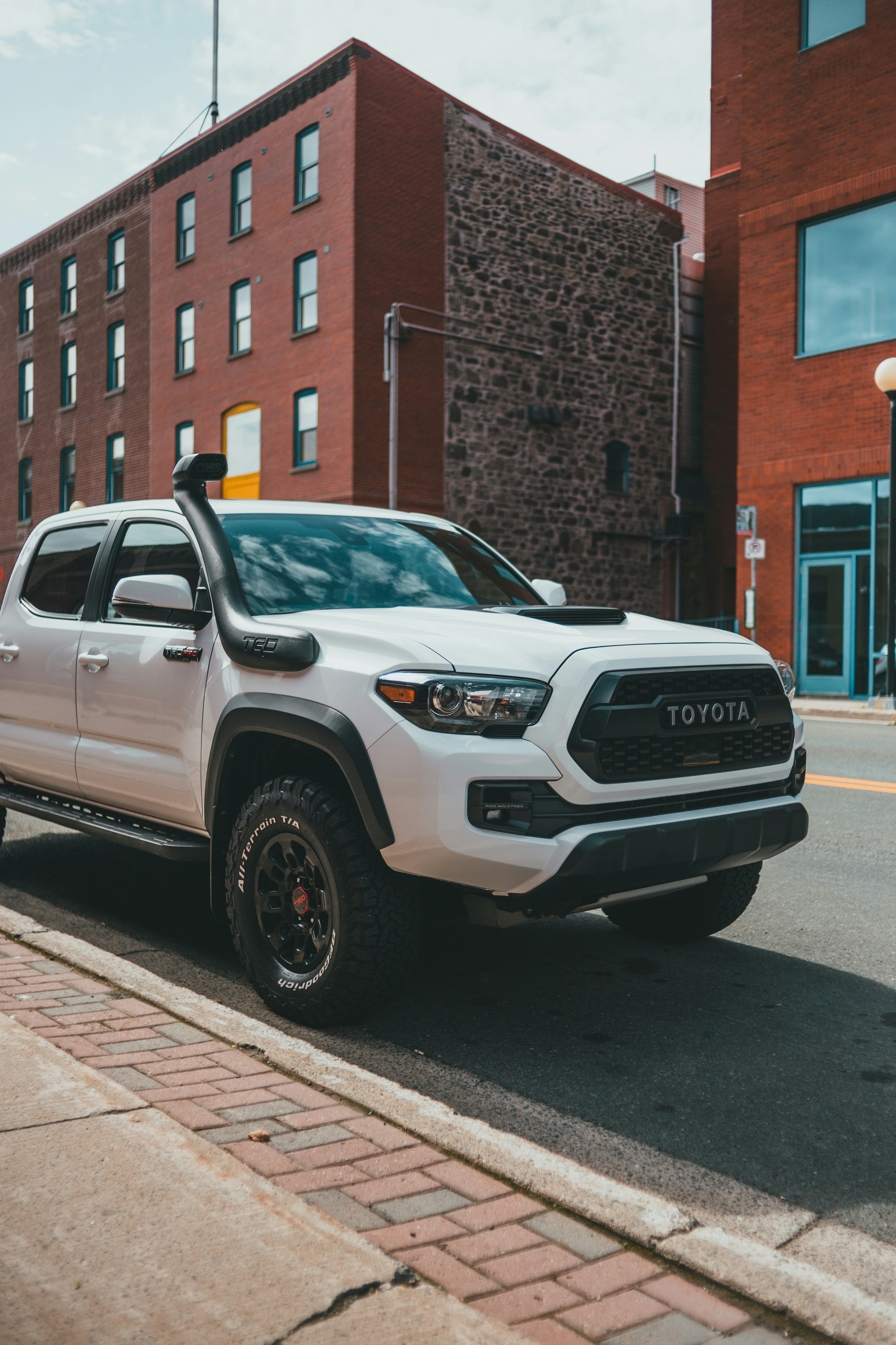 white nissan crew cab pickup truck parked on sidewalk during daytime
