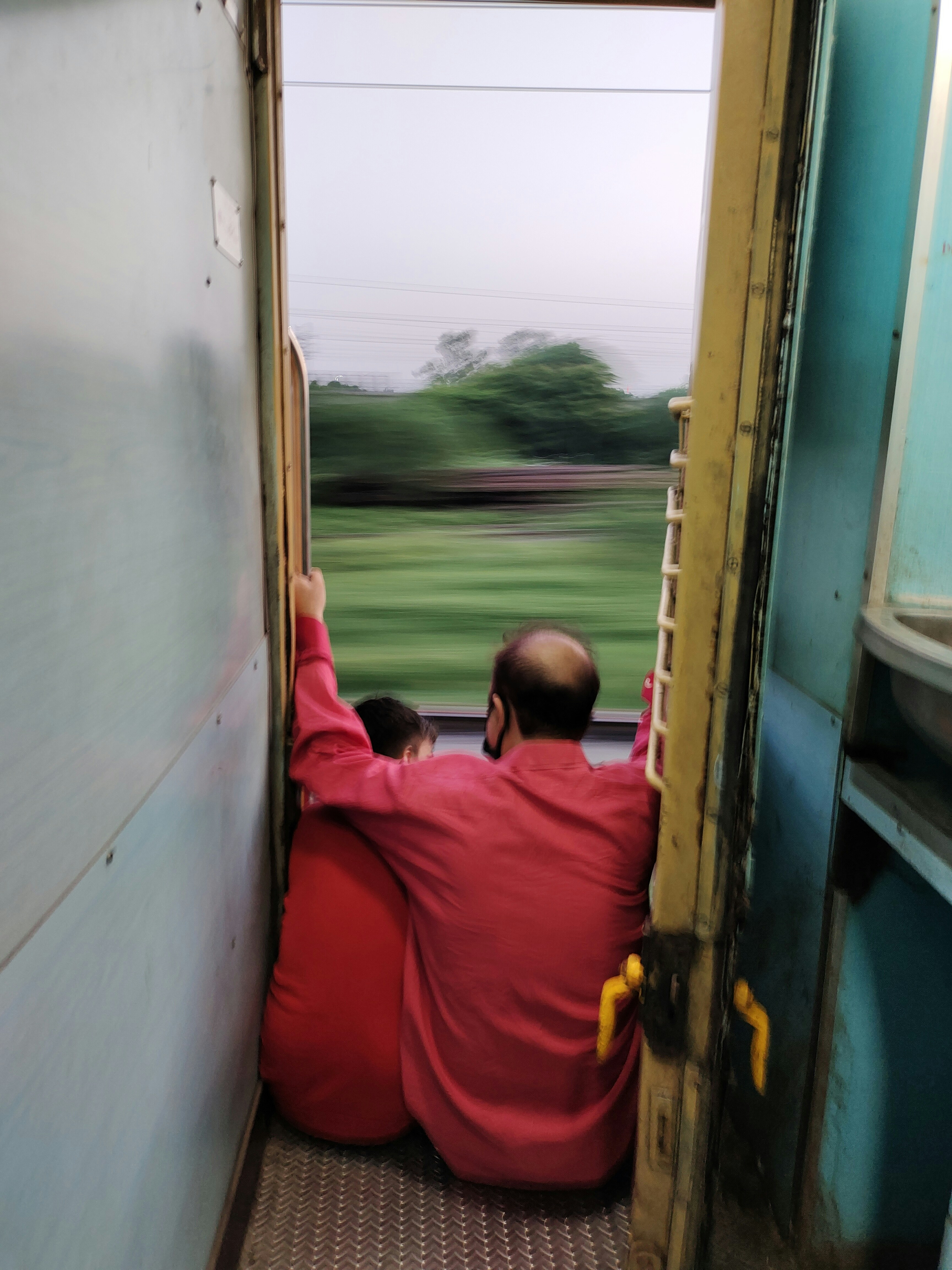 Red-Clad Duo Huddled in a Moving Train Corridor