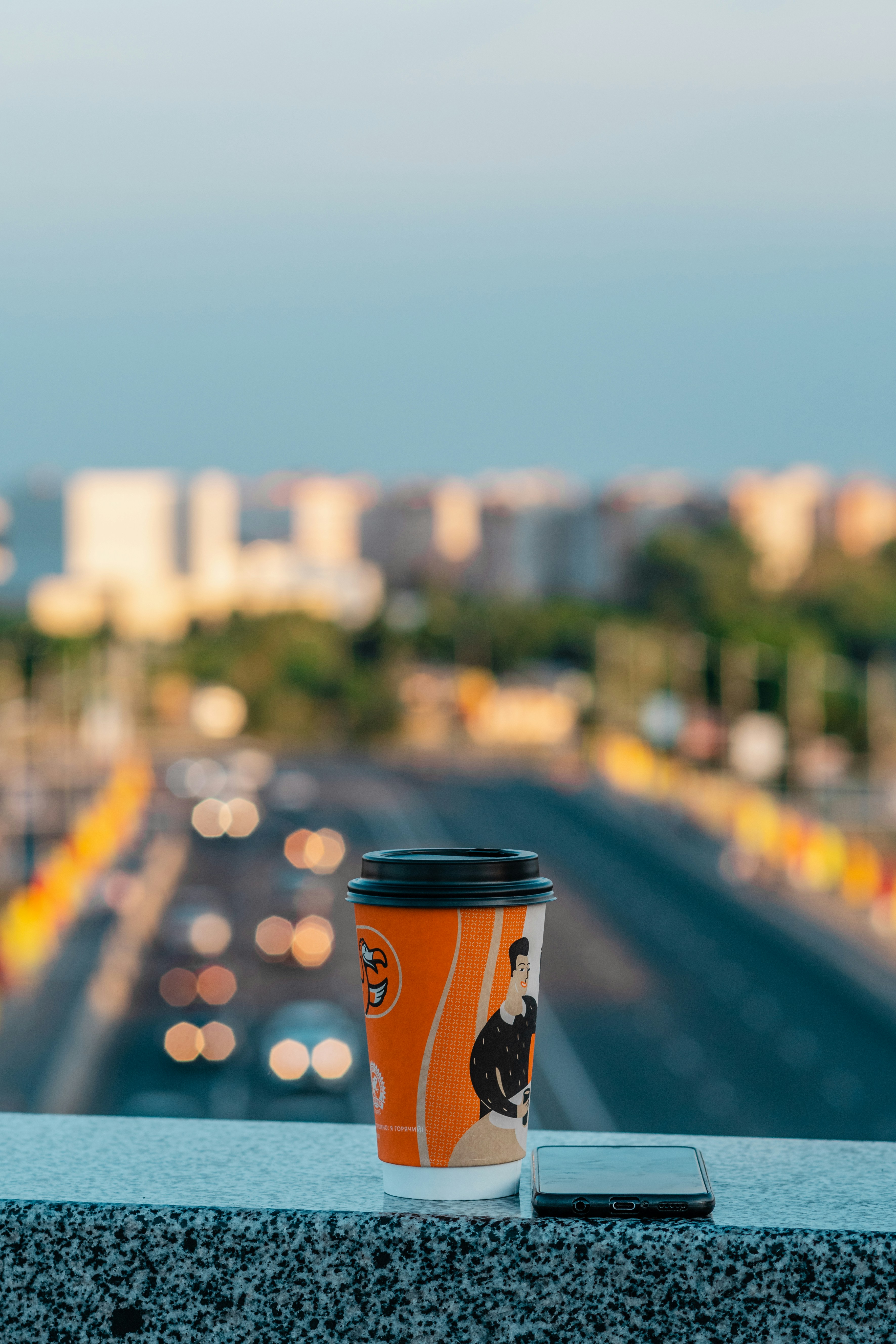 Espresso at the Brink: A Cup in Focus Over a Blurred City Boulevard