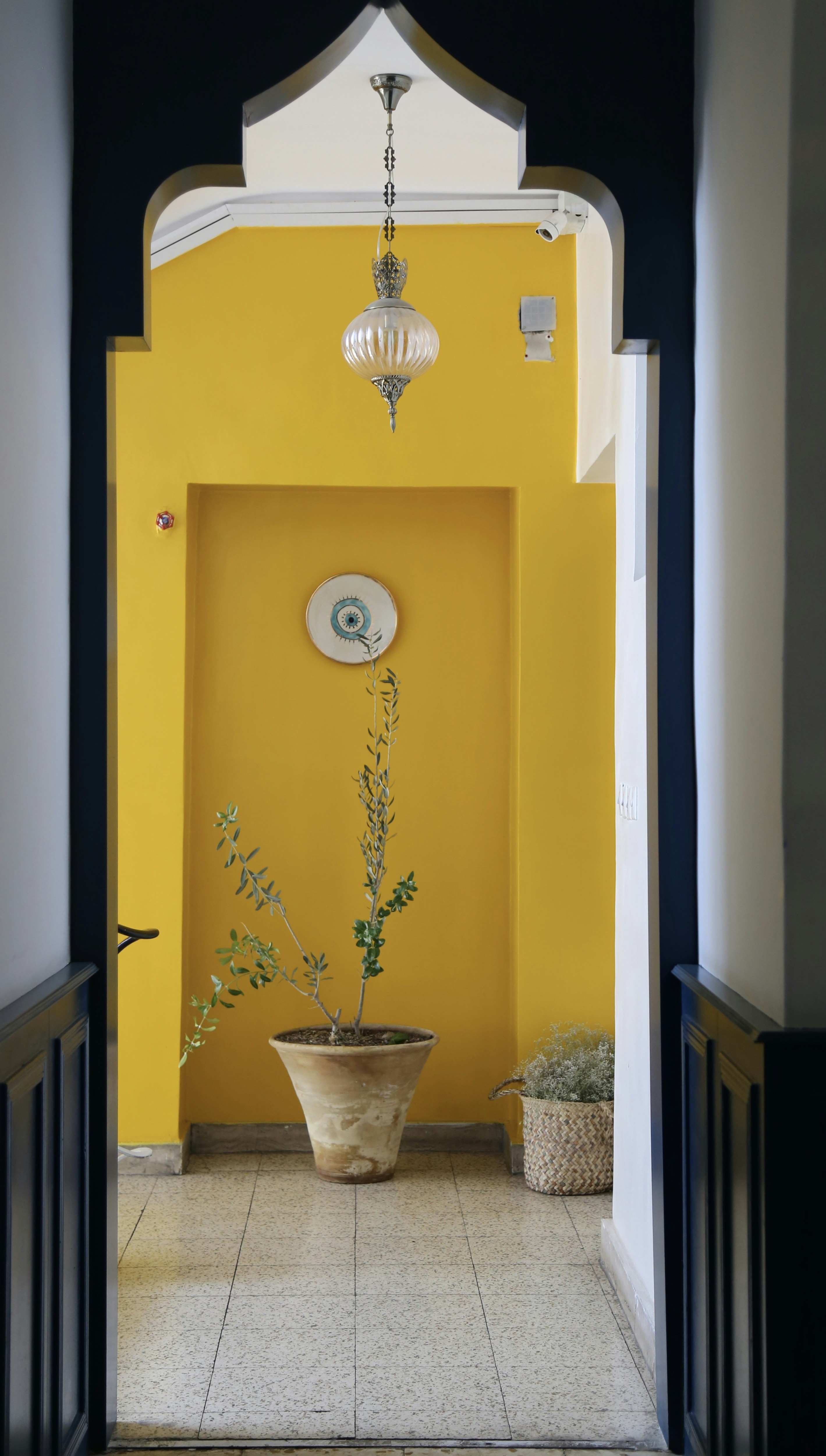 Through the Arch to a Yellow Atrium: Lantern, Plant, and Cerulean Eye