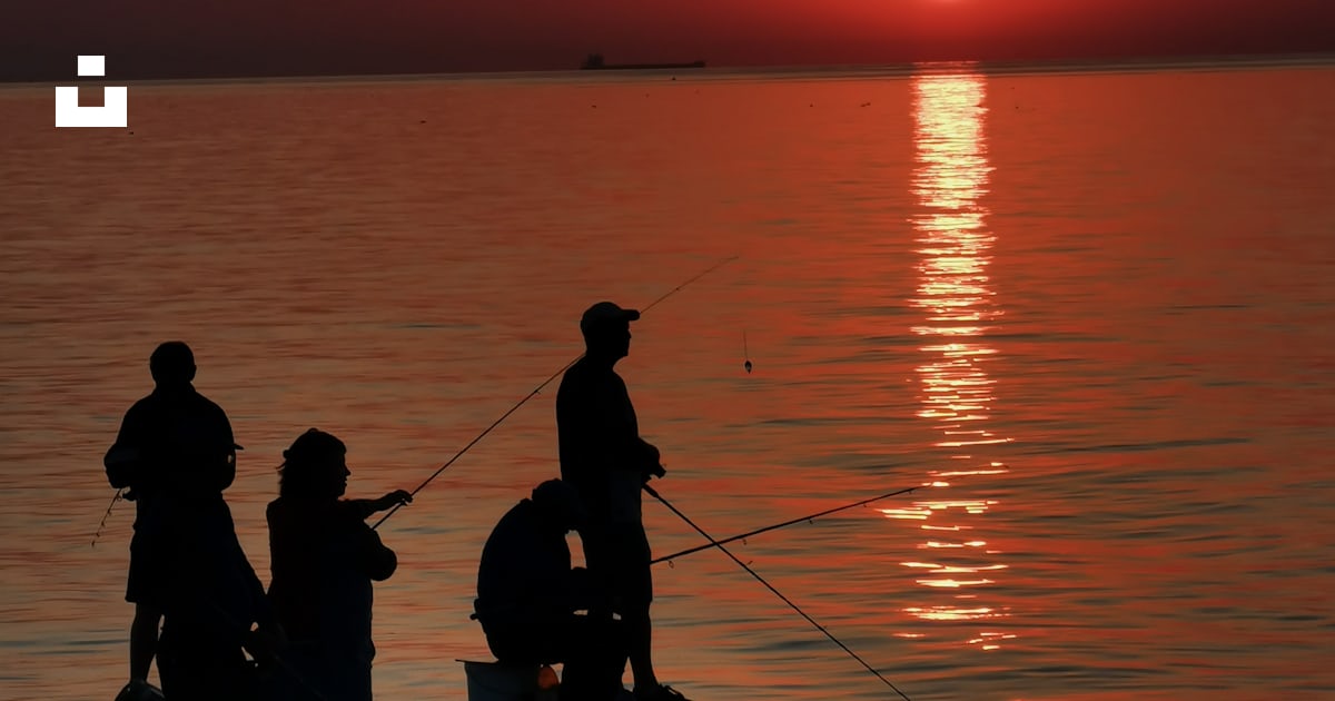 Silueta De Personas De Pie En El Muelle Durante La Puesta Del Sol Foto