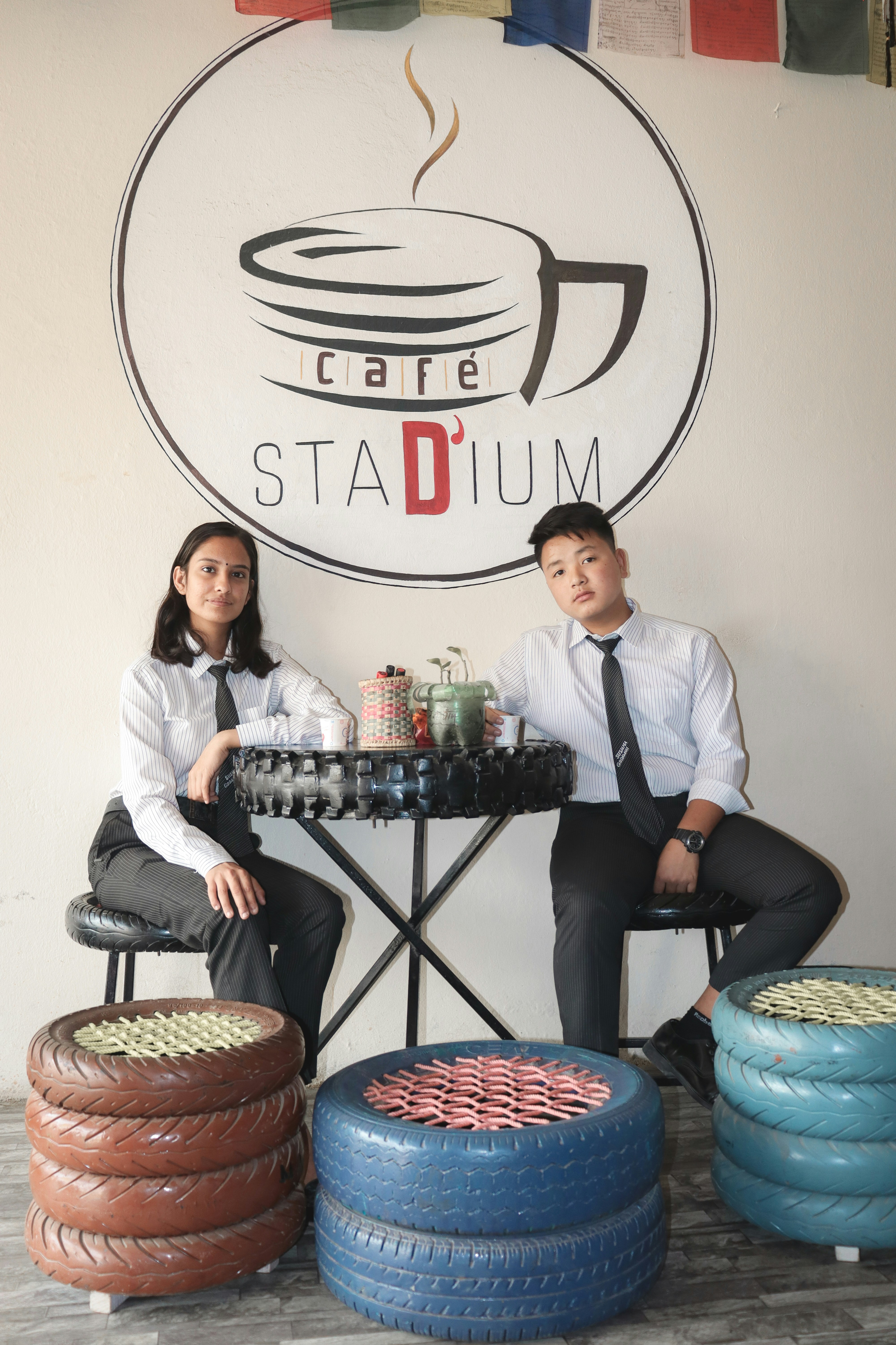 Uniformed Duo at a Tire-Seated Café Beneath a Circular Coffee Logo