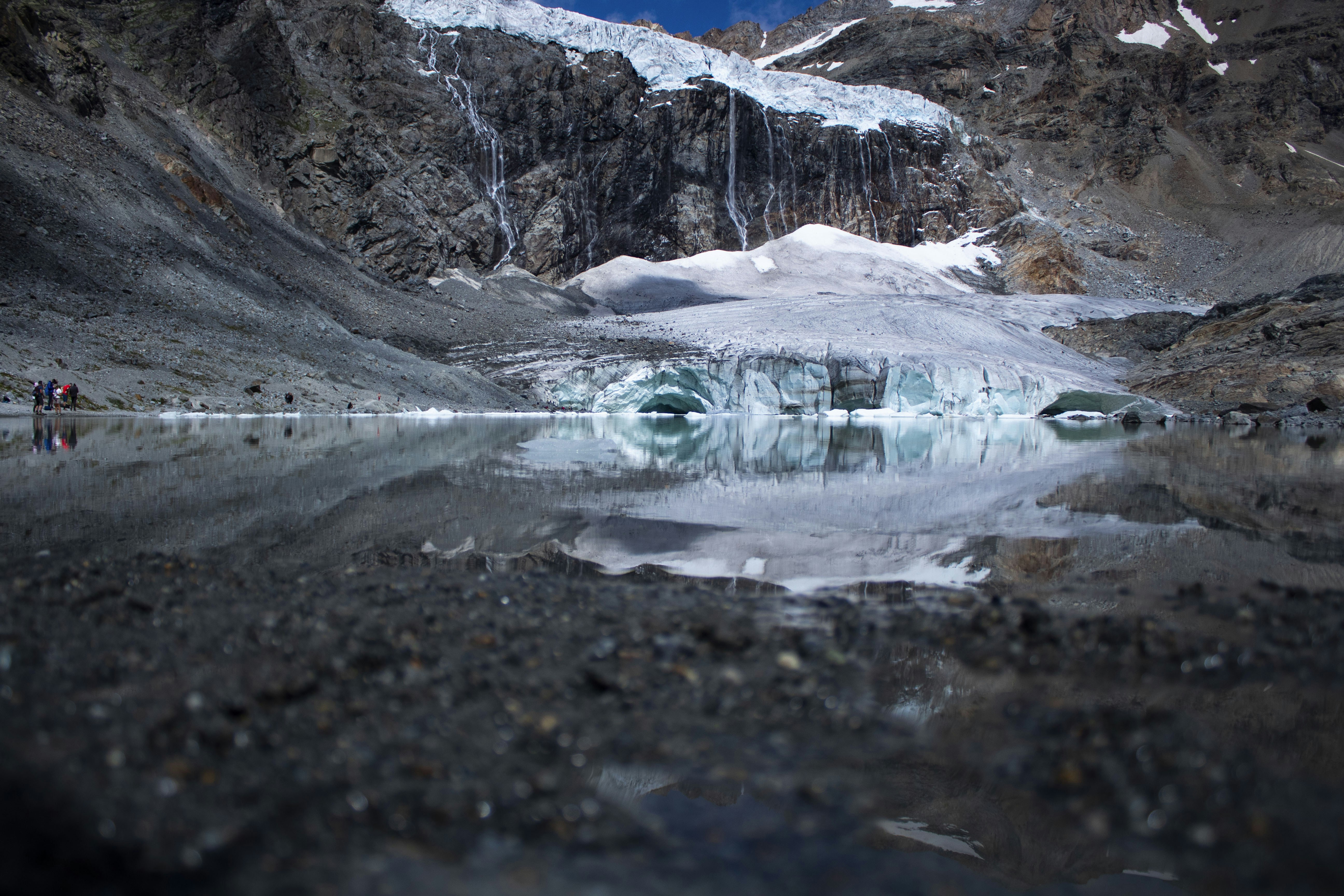 Snow-capped mountain reflected in a tranquil alpine lake under a clear blue sky.