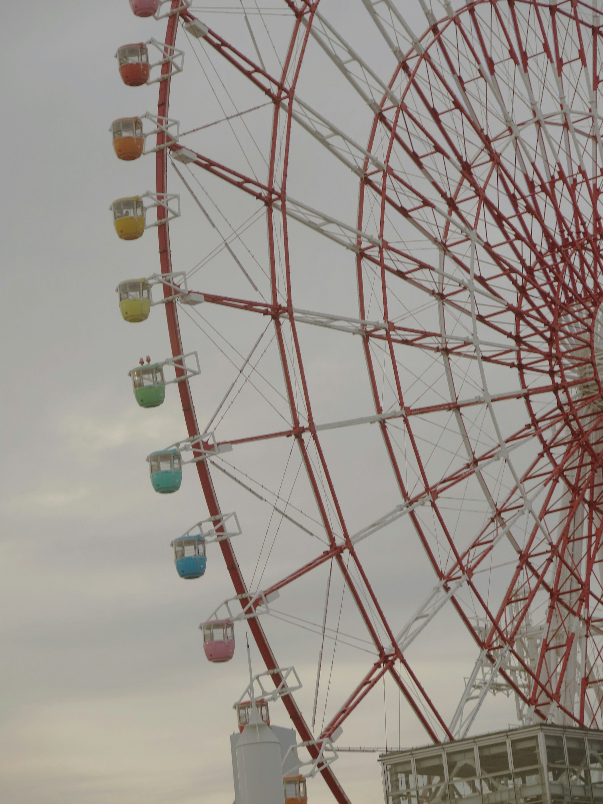 A vibrant ferris wheel adorned with colorful gondolas against a soft, cloudy sky.