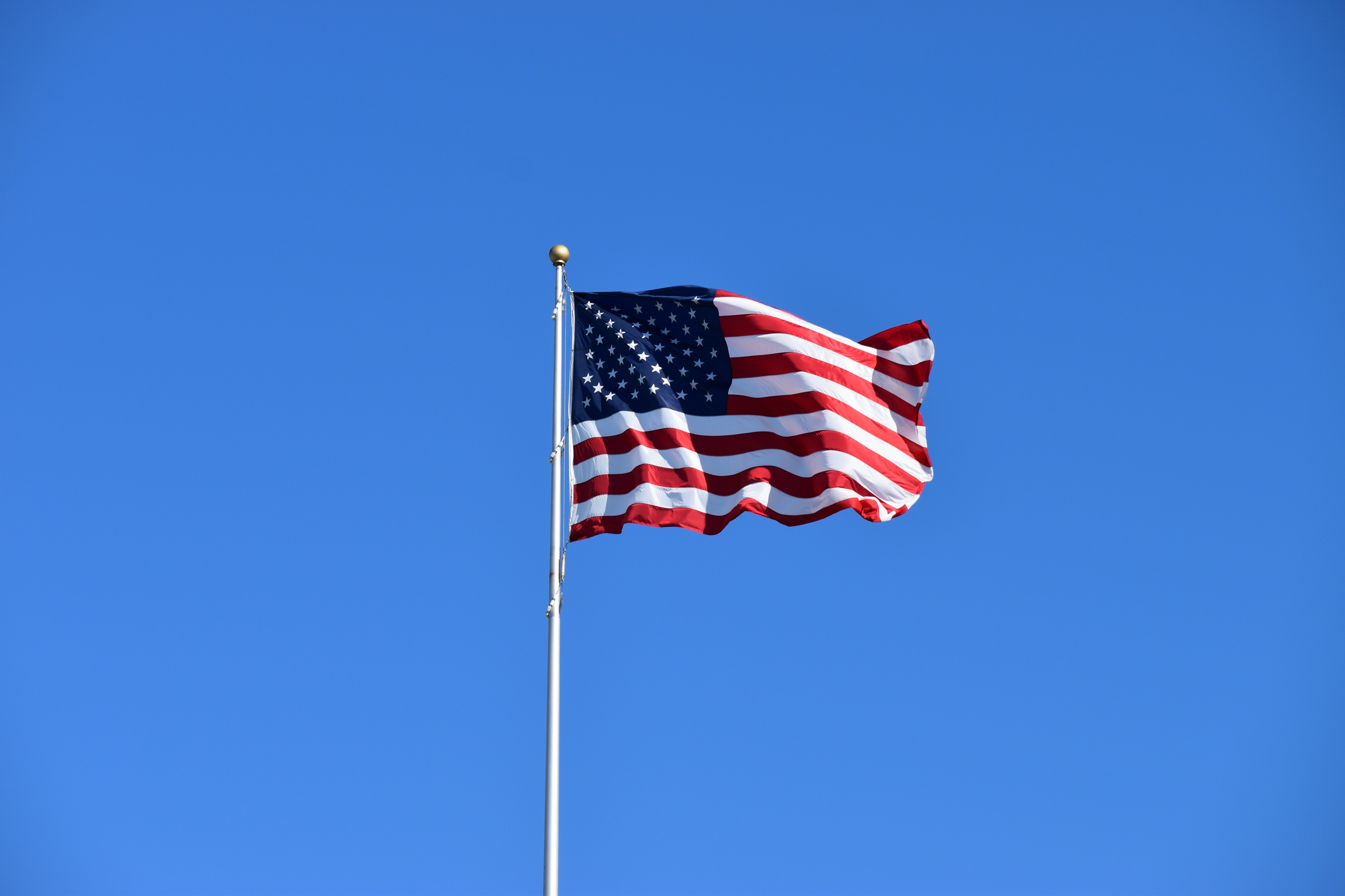 American flag fluttering proudly against a vibrant blue sky.