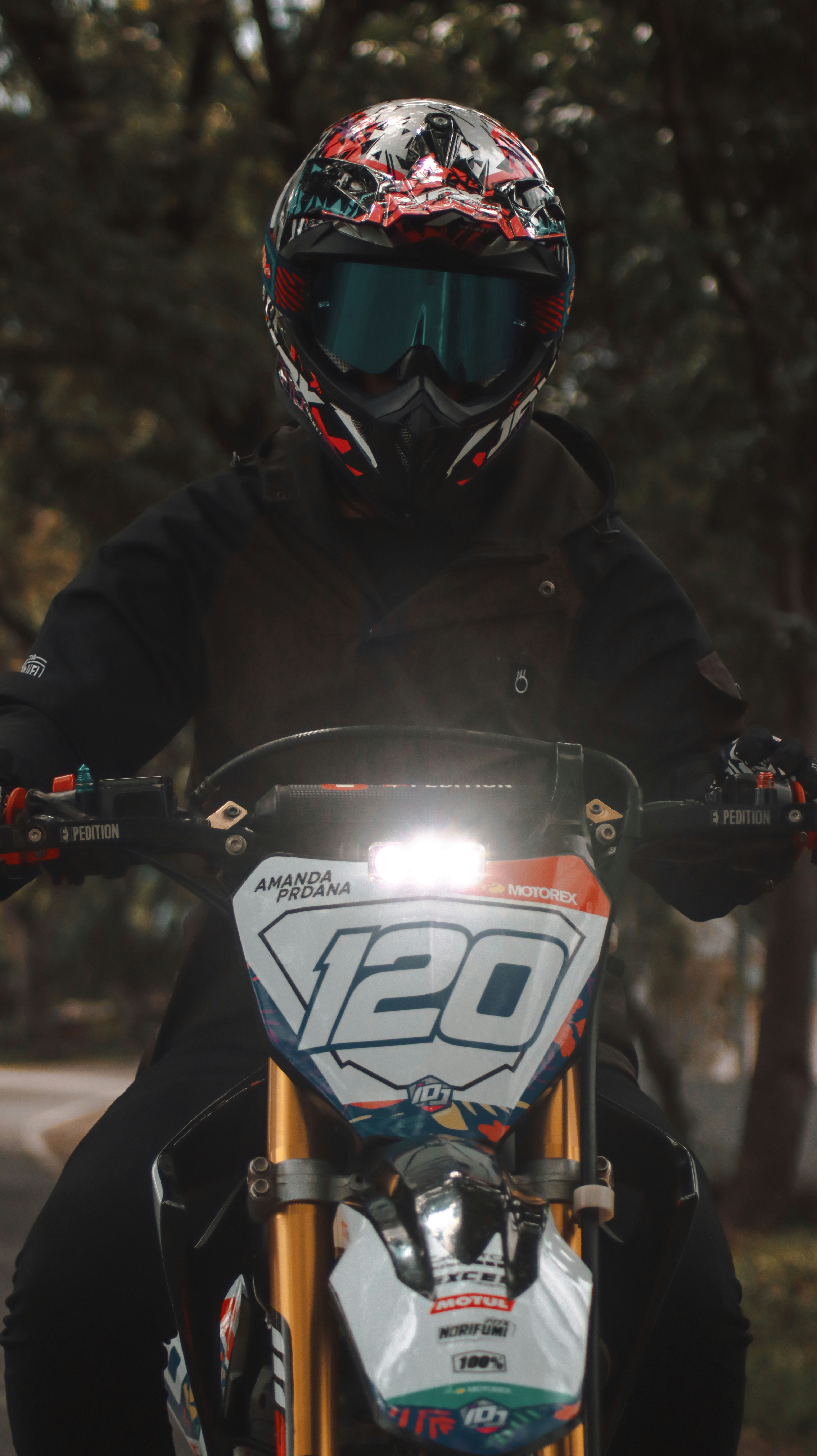 Nocturnal Dash: Helmeted Rider on a 120 Dirt Bike Through Shadowed Pines