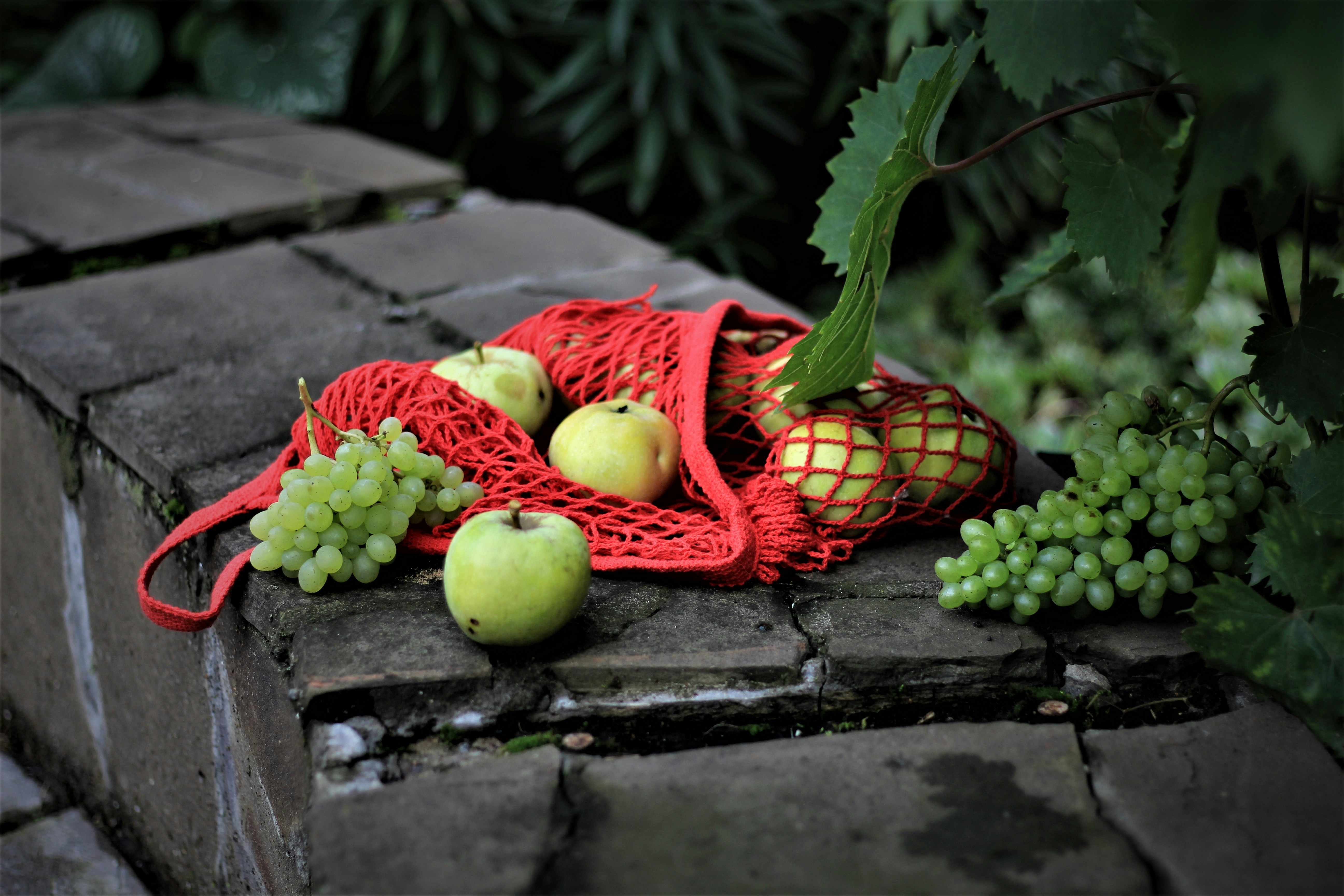 Crimson Mesh Cradling Green Apples on Weathered Stone Steps