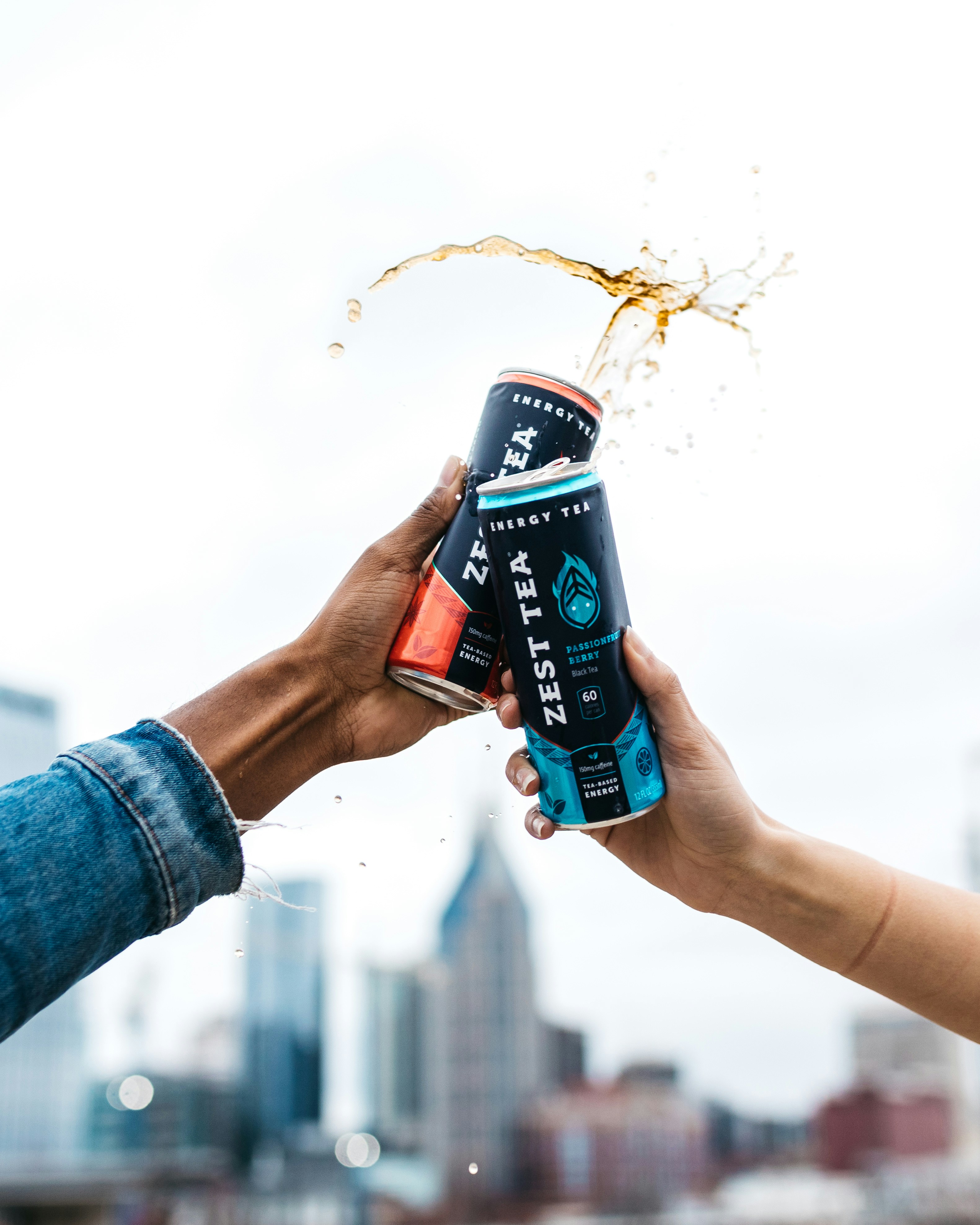 Urban Toast: A Pair of Energy Cans Arc Over a Blurred Skyline