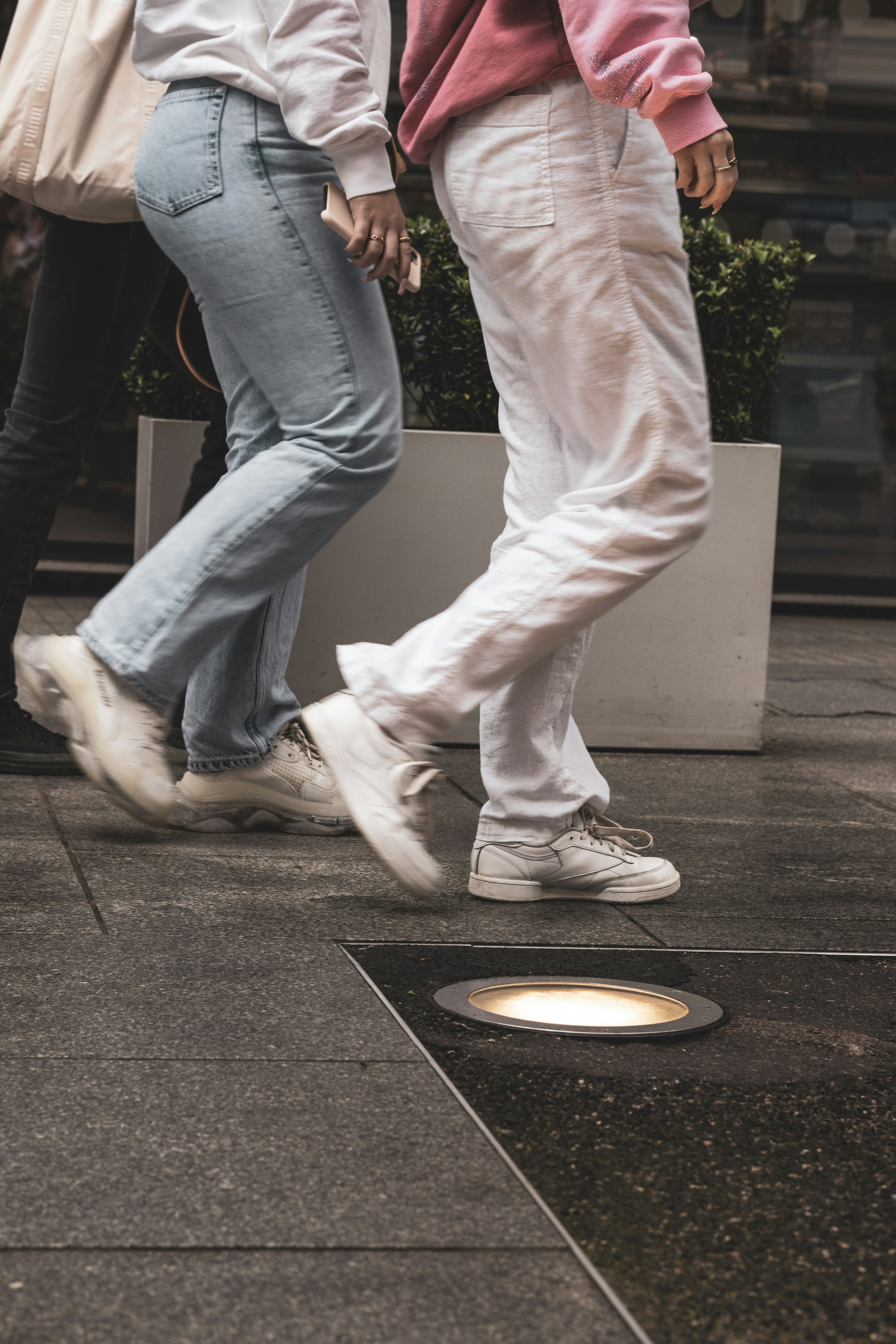 person in blue denim jeans and white shoes standing on gray concrete floor