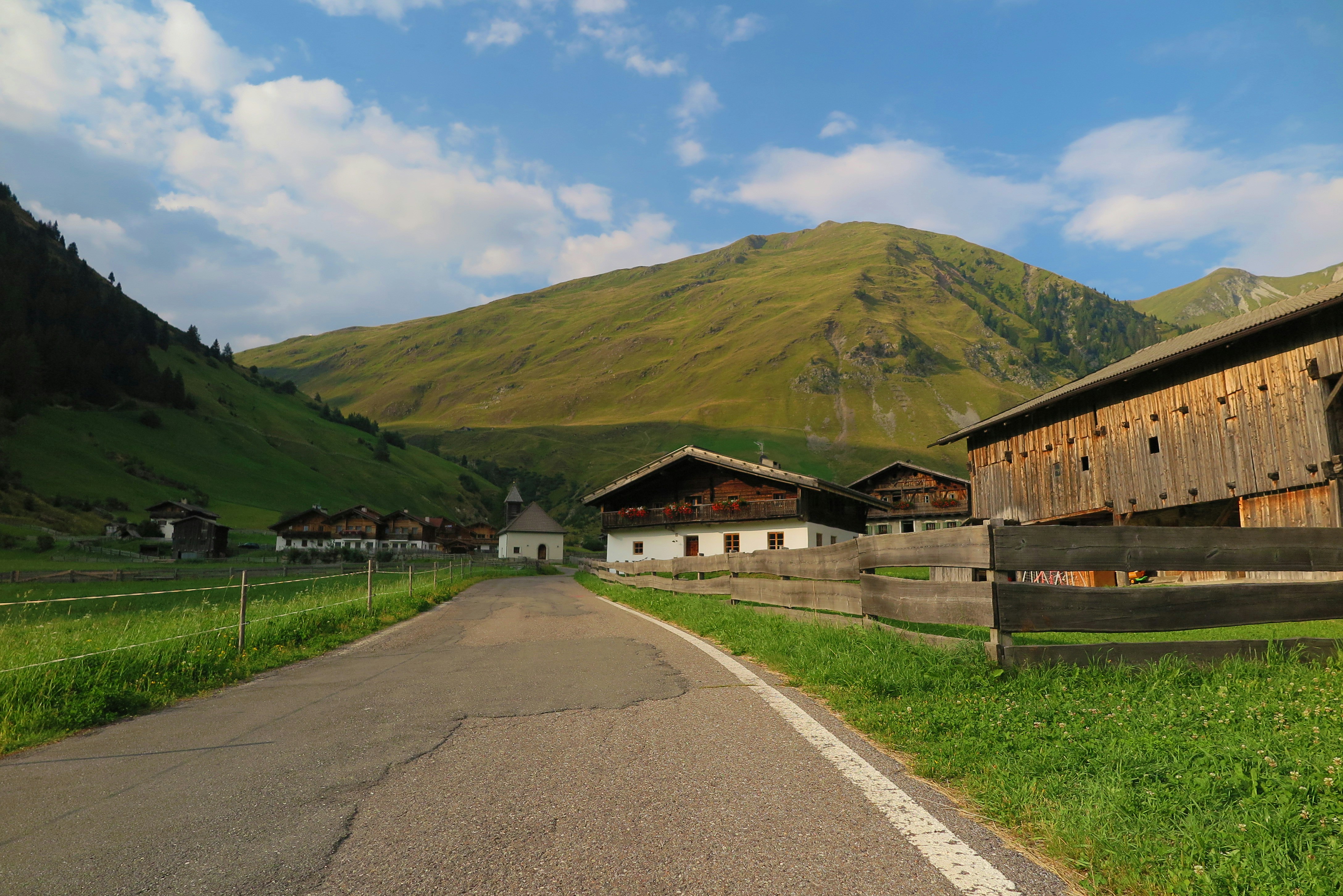 brown wooden house near green mountain under blue sky during daytime