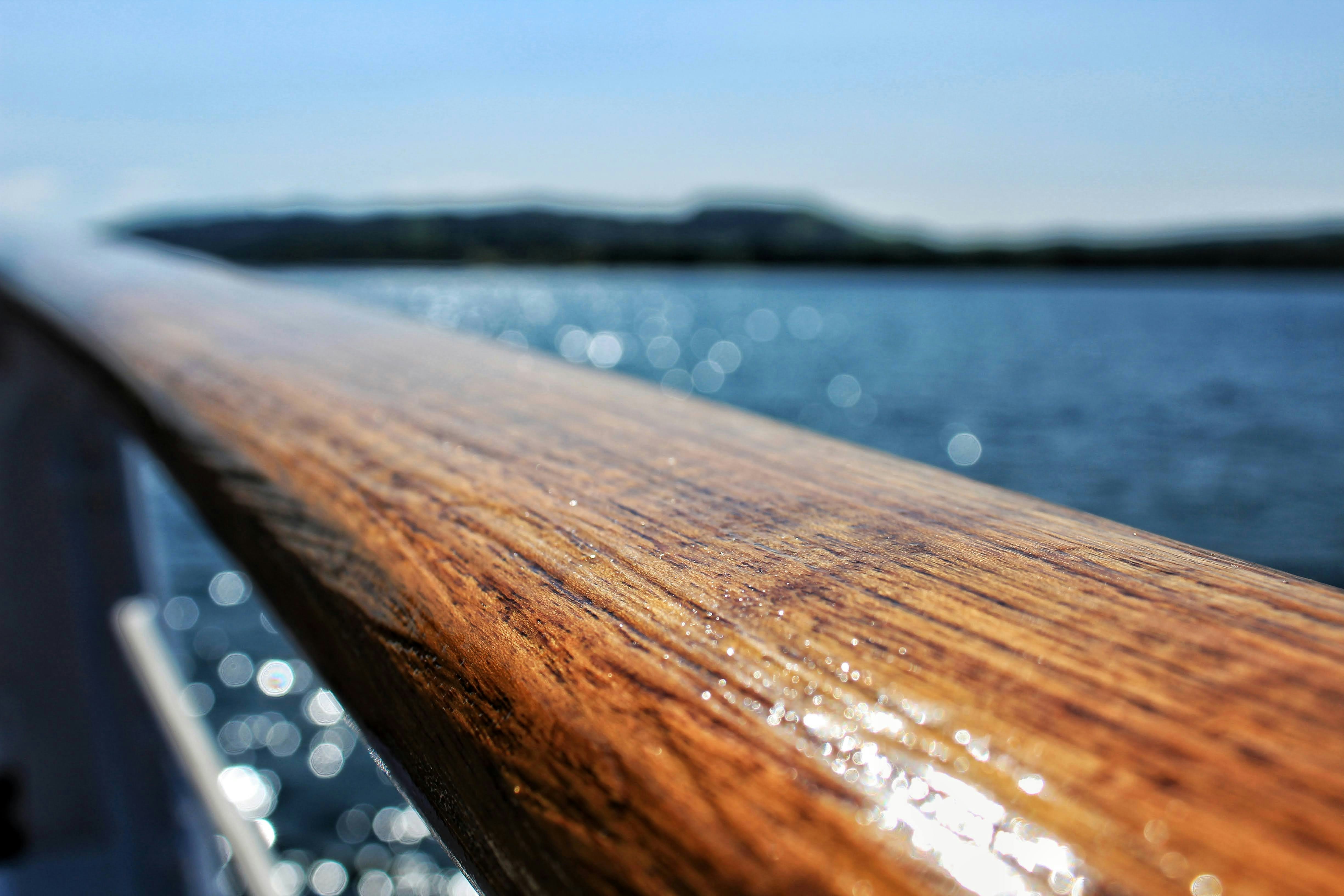 Sunlit Wood Grain on a Boat Rail, with a Distant Blue Sea