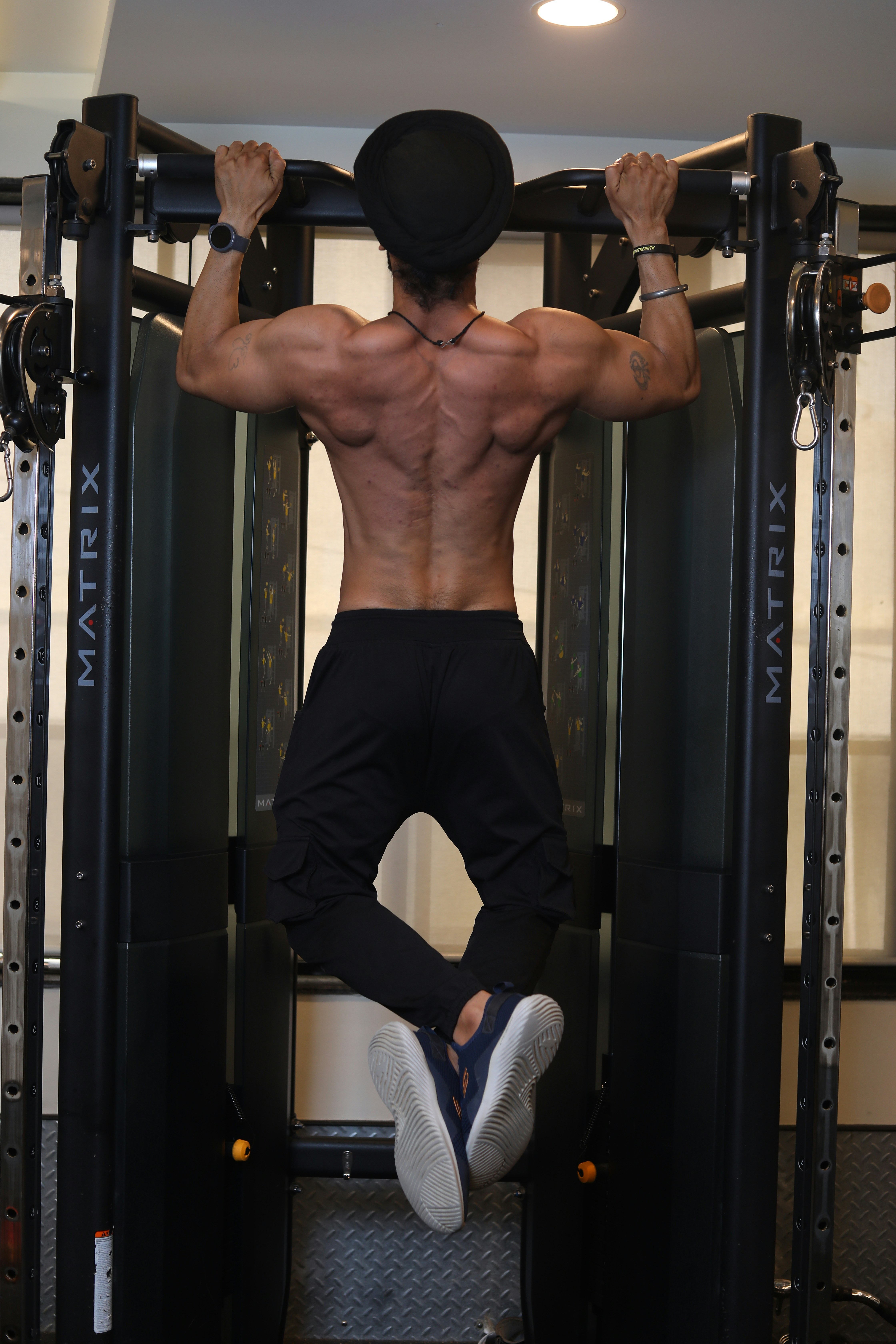 Athlete performing pull-ups on a MATRIX gym machine, showcasing muscular definition and focused determination.
