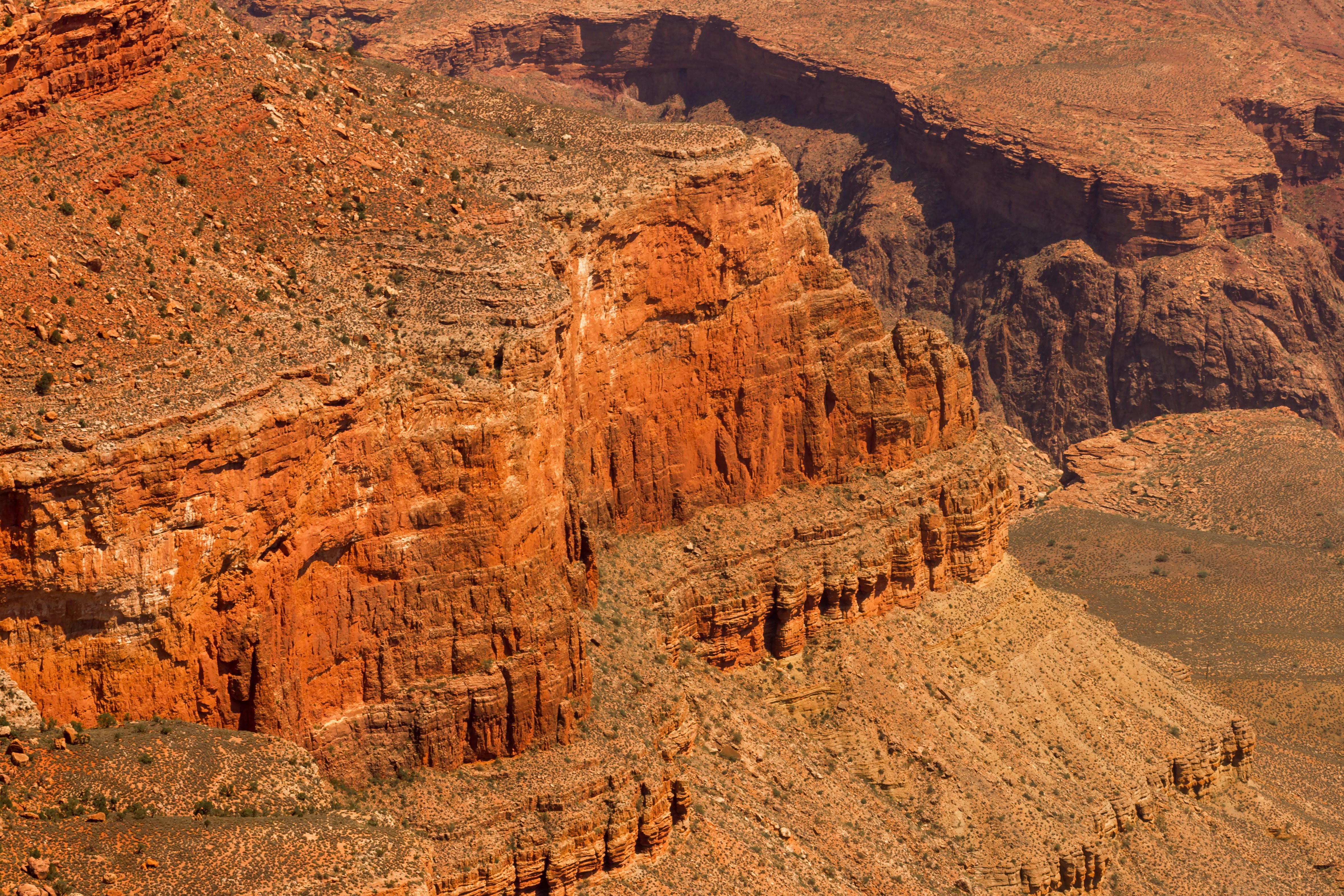 Vivid red cliffs showcasing the intricate layers of geological history in a rugged landscape. The natural formations highlight the power of erosion over millennia.