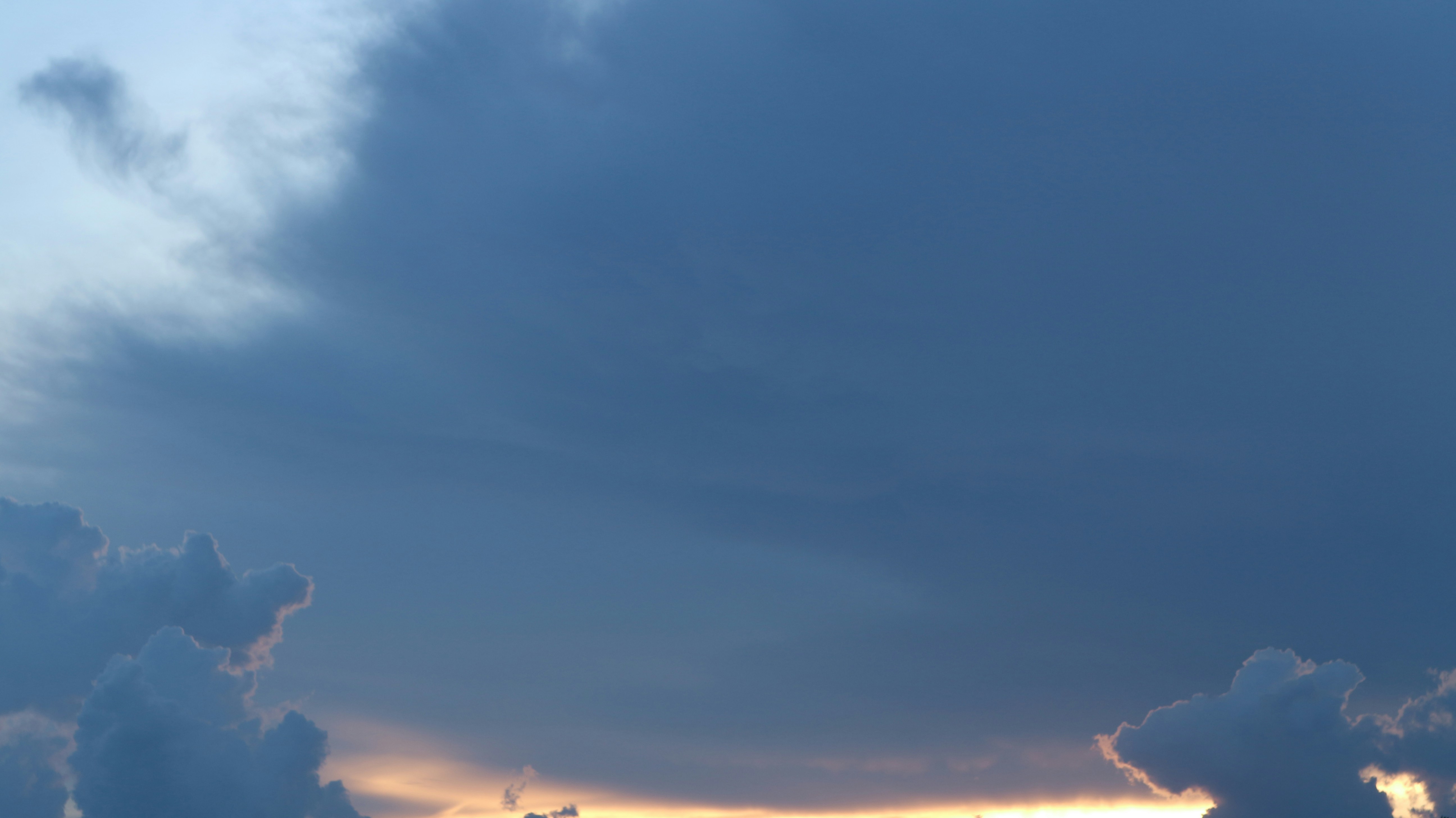 Dramatic cloud formations illuminated by the fading light of sunset, creating a serene and contemplative atmosphere.