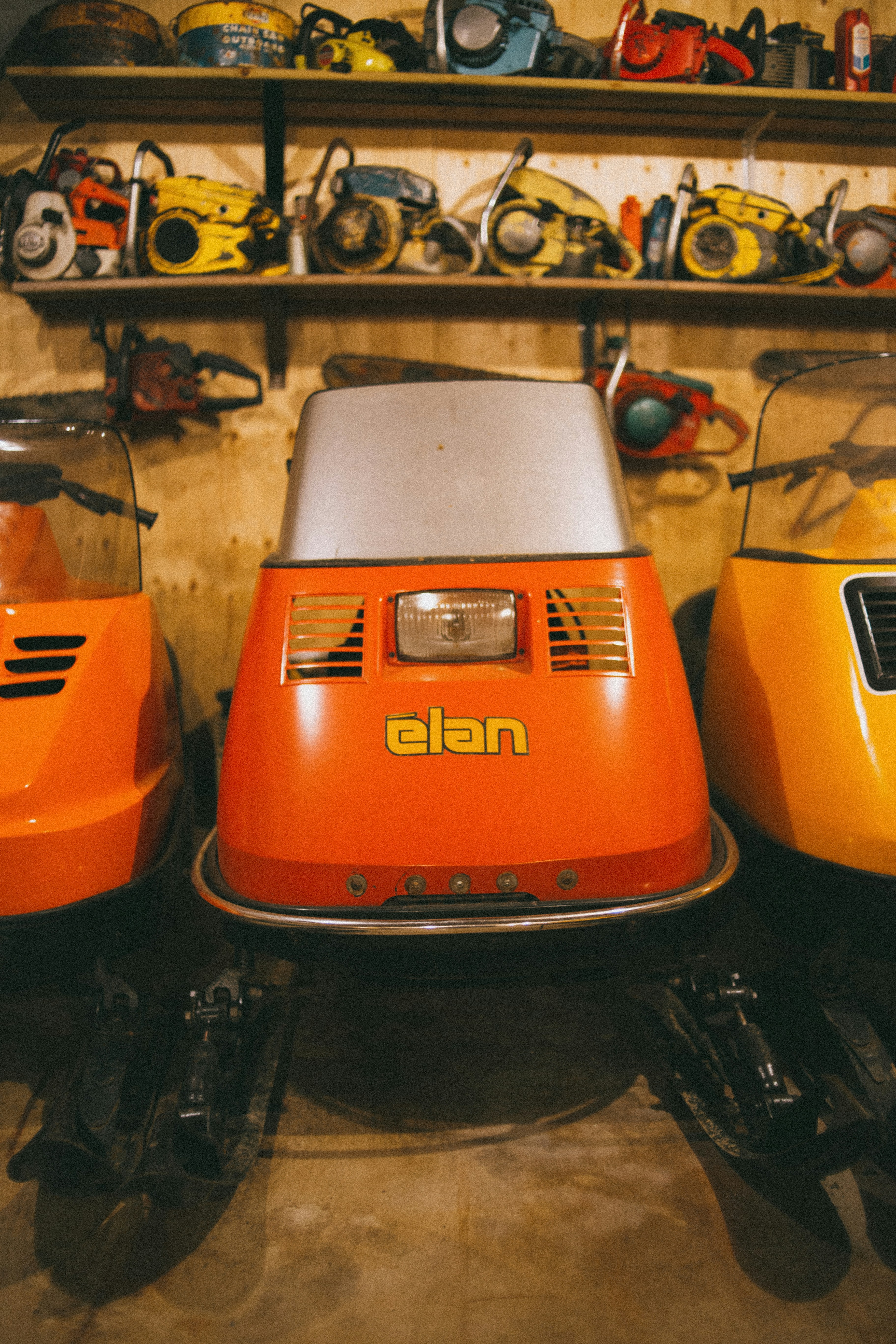 Red snowmobile in a workshop lined with gear