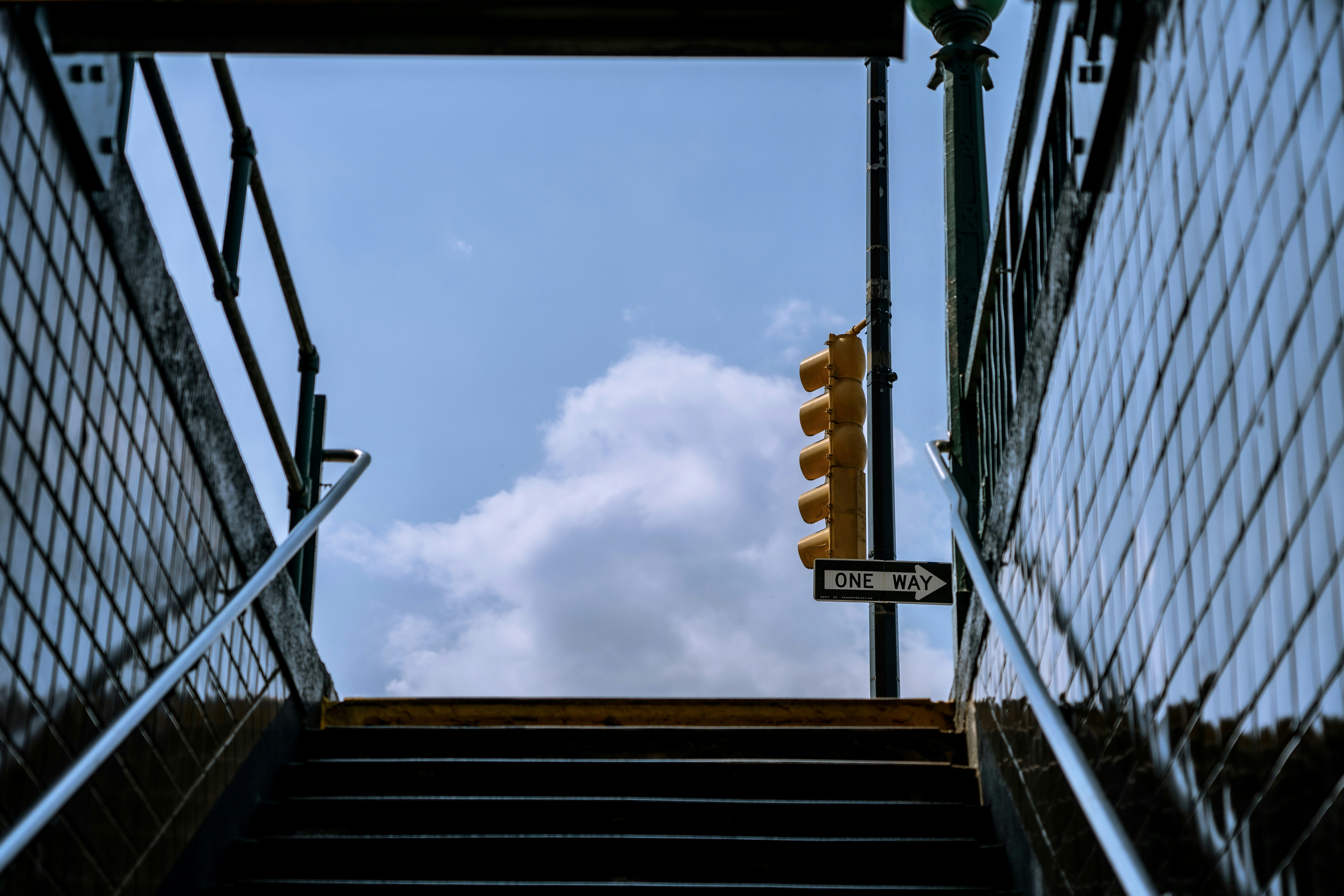 Between Rails and Sky: A Narrow Staircase Framing a Yellow Traffic Light