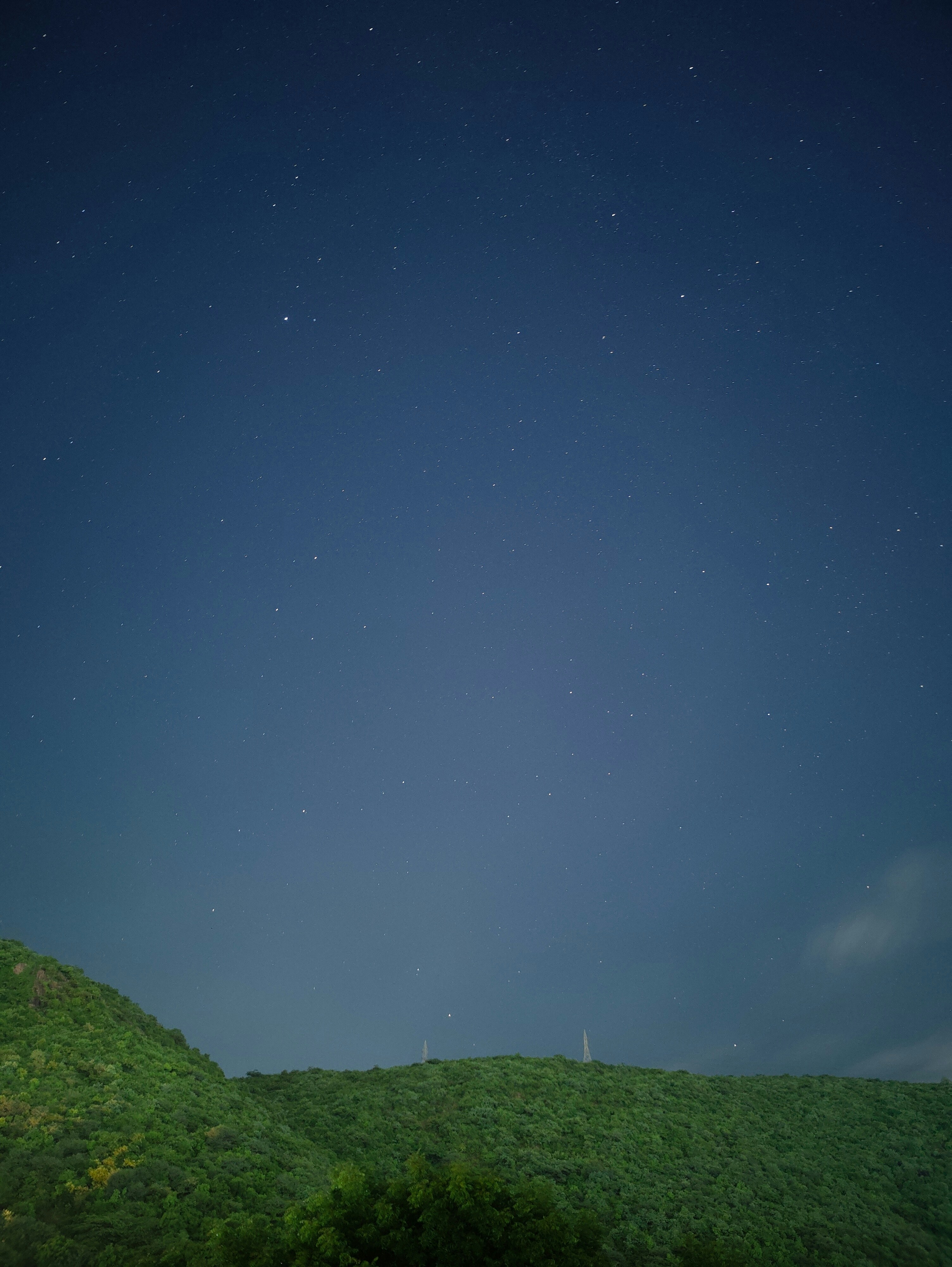 Night sky filled with stars over rolling green hills, captured as a tranquil landscape photograph.