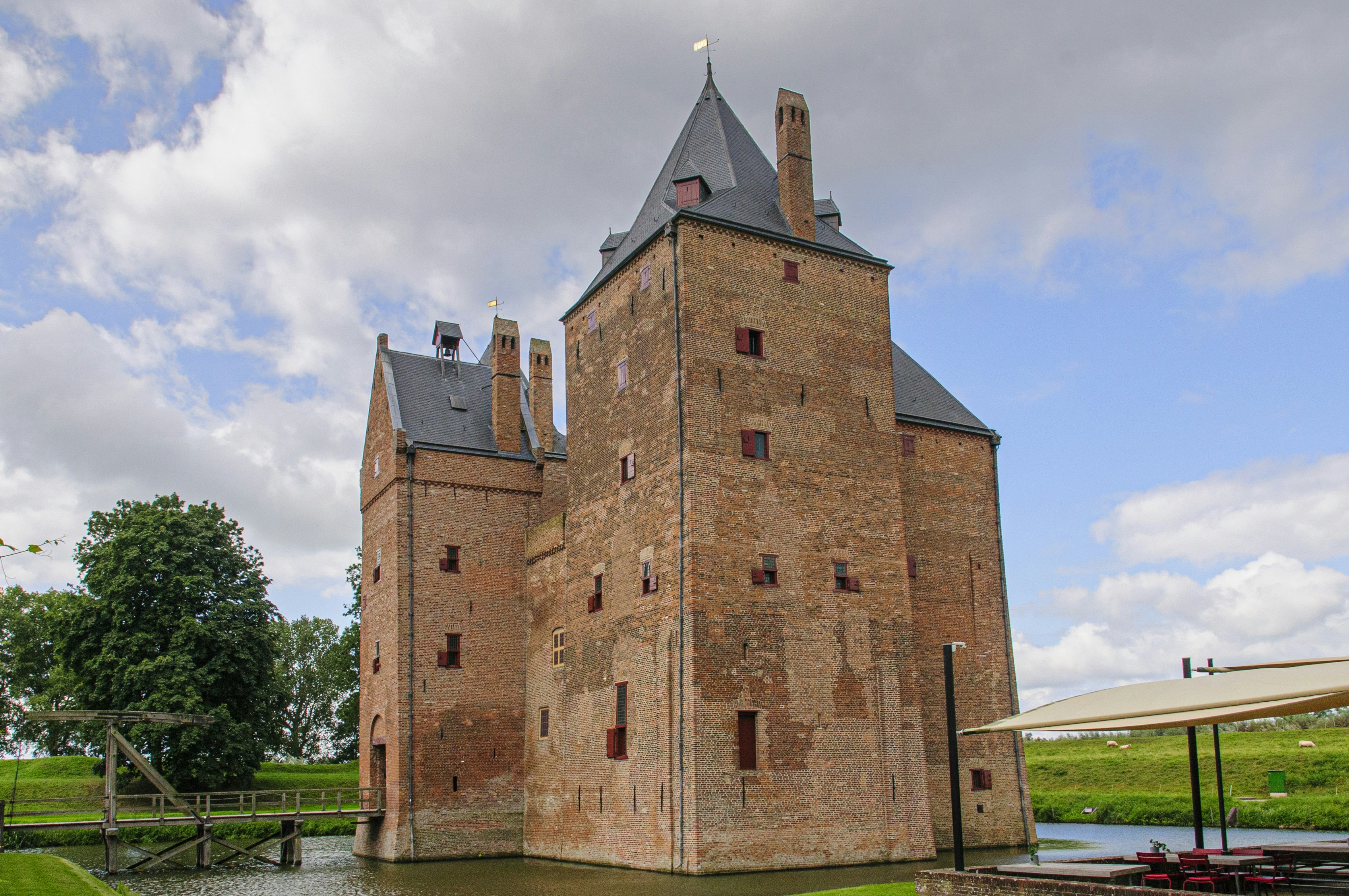 Historic castle with red brick towers set against a partly cloudy sky.