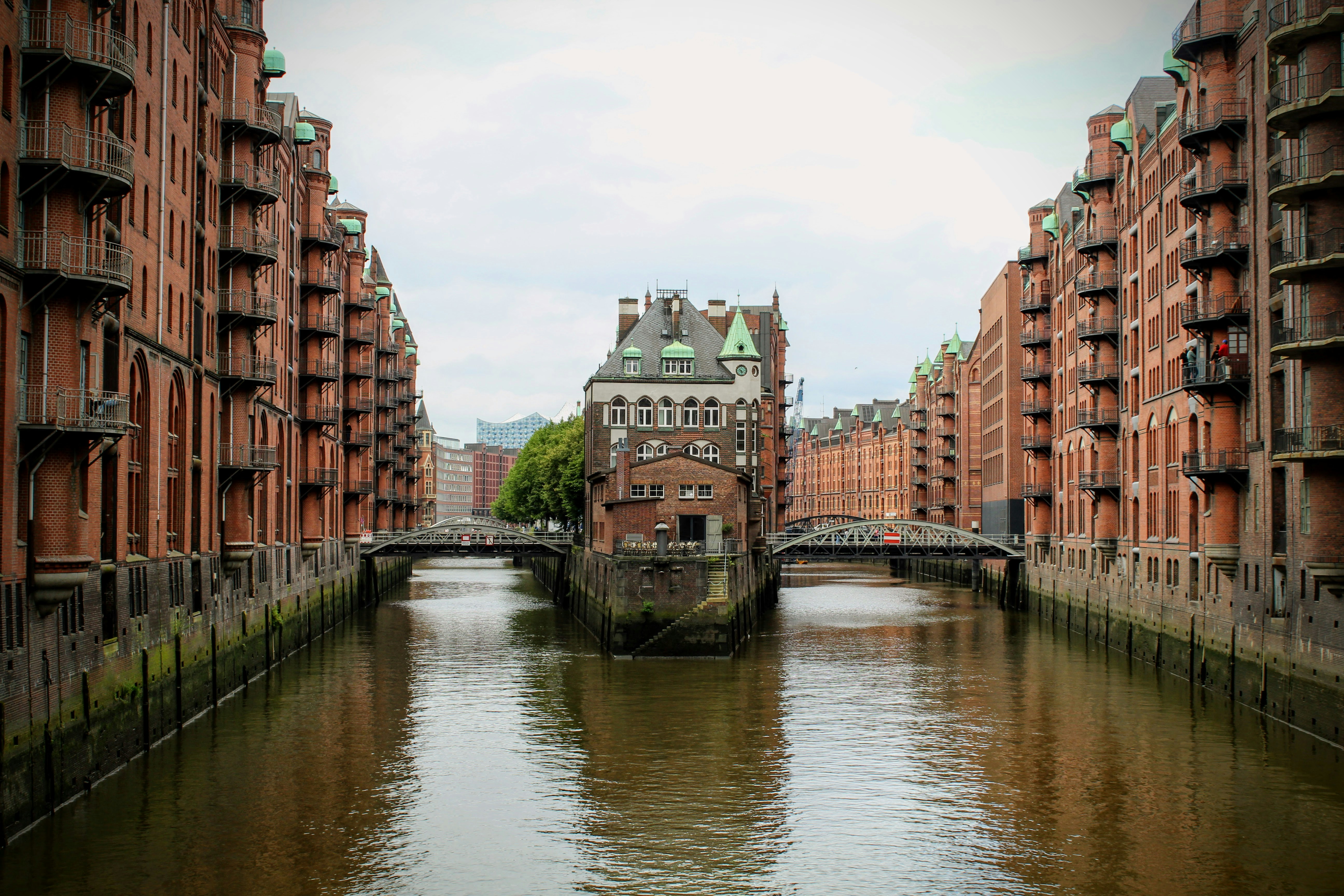 Historic brick buildings line a canal under a cloudy sky.