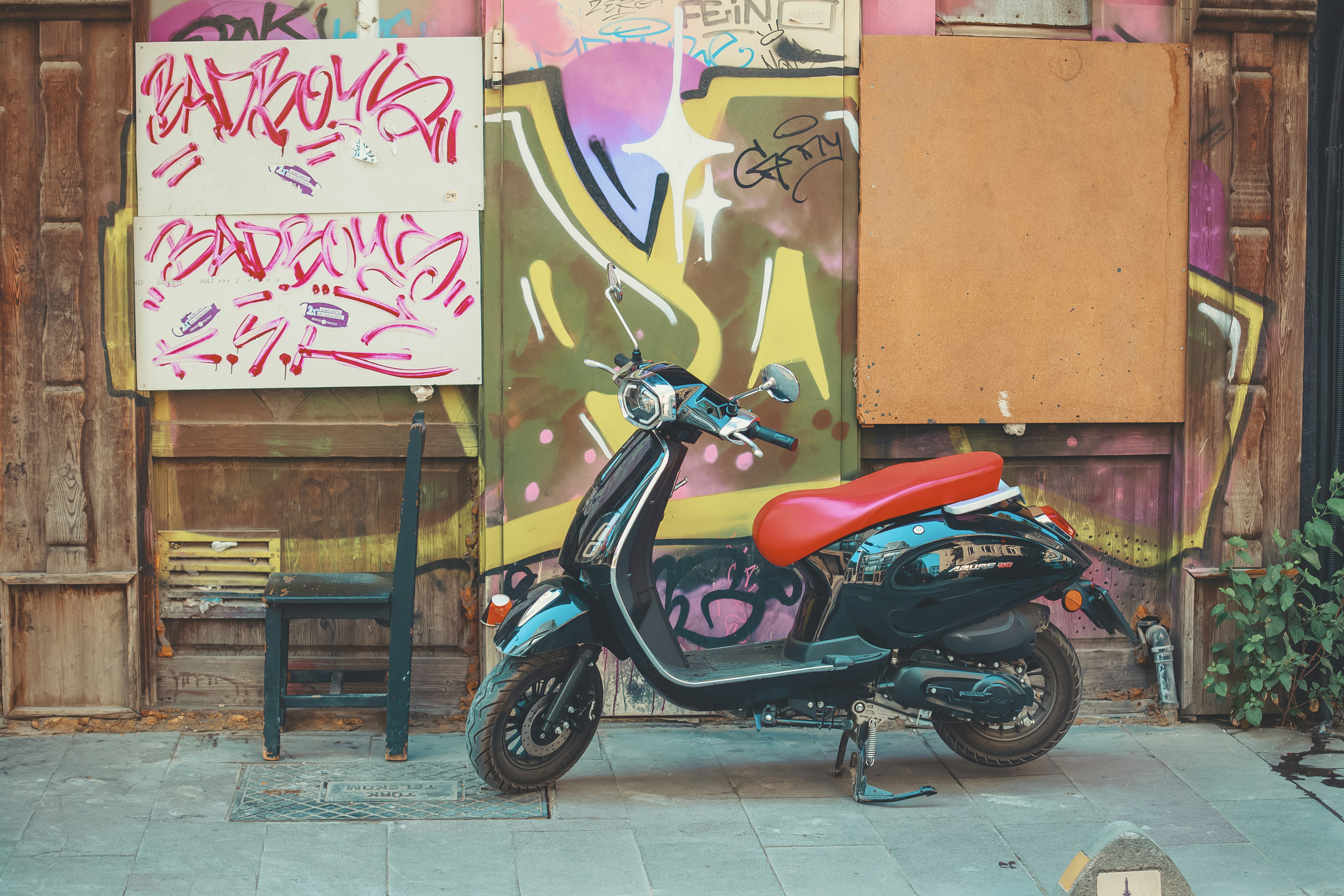 red and black motorcycle parked beside brown wooden fence