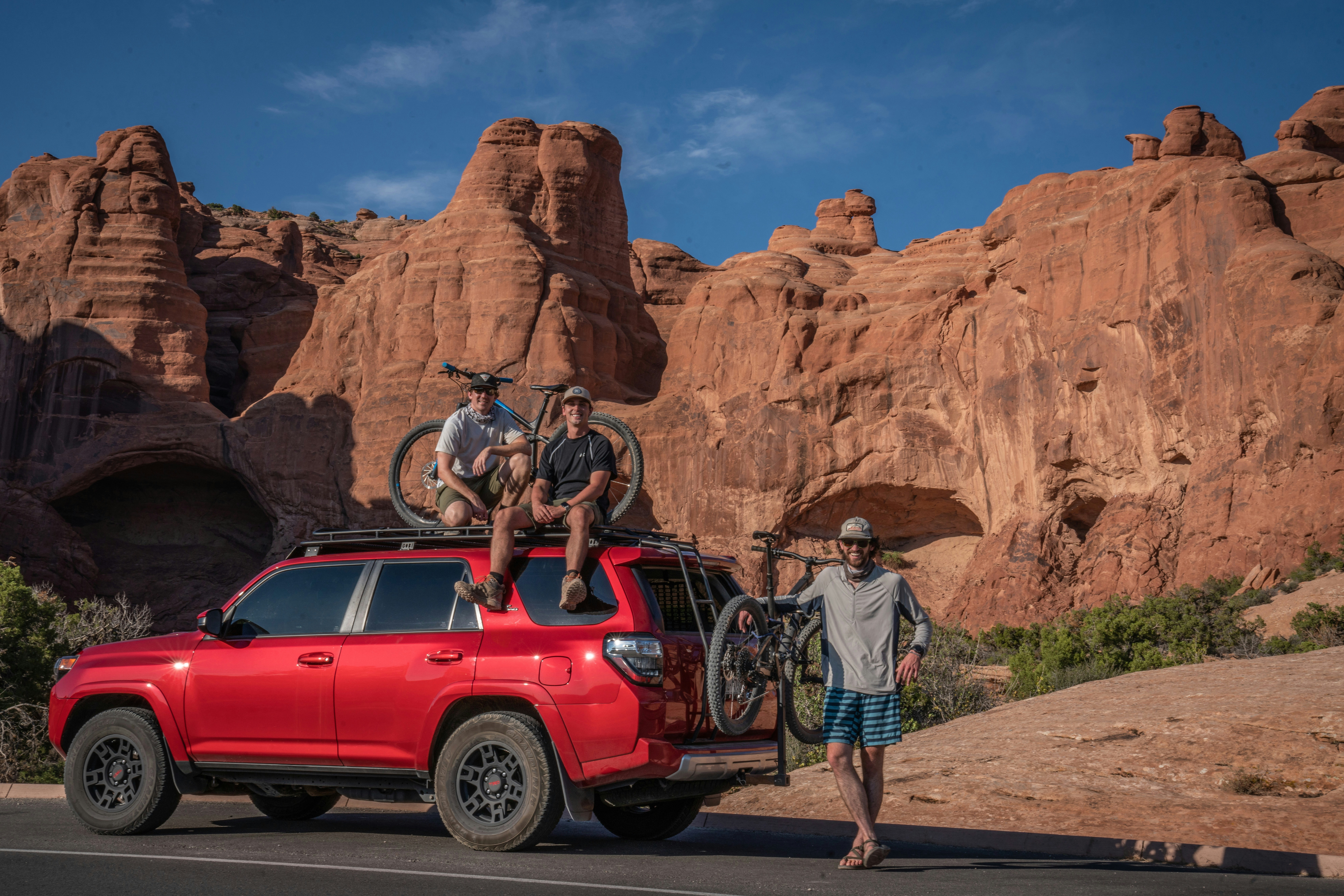 Desert Rally: Riders, Red SUV, and Rocky Peaks