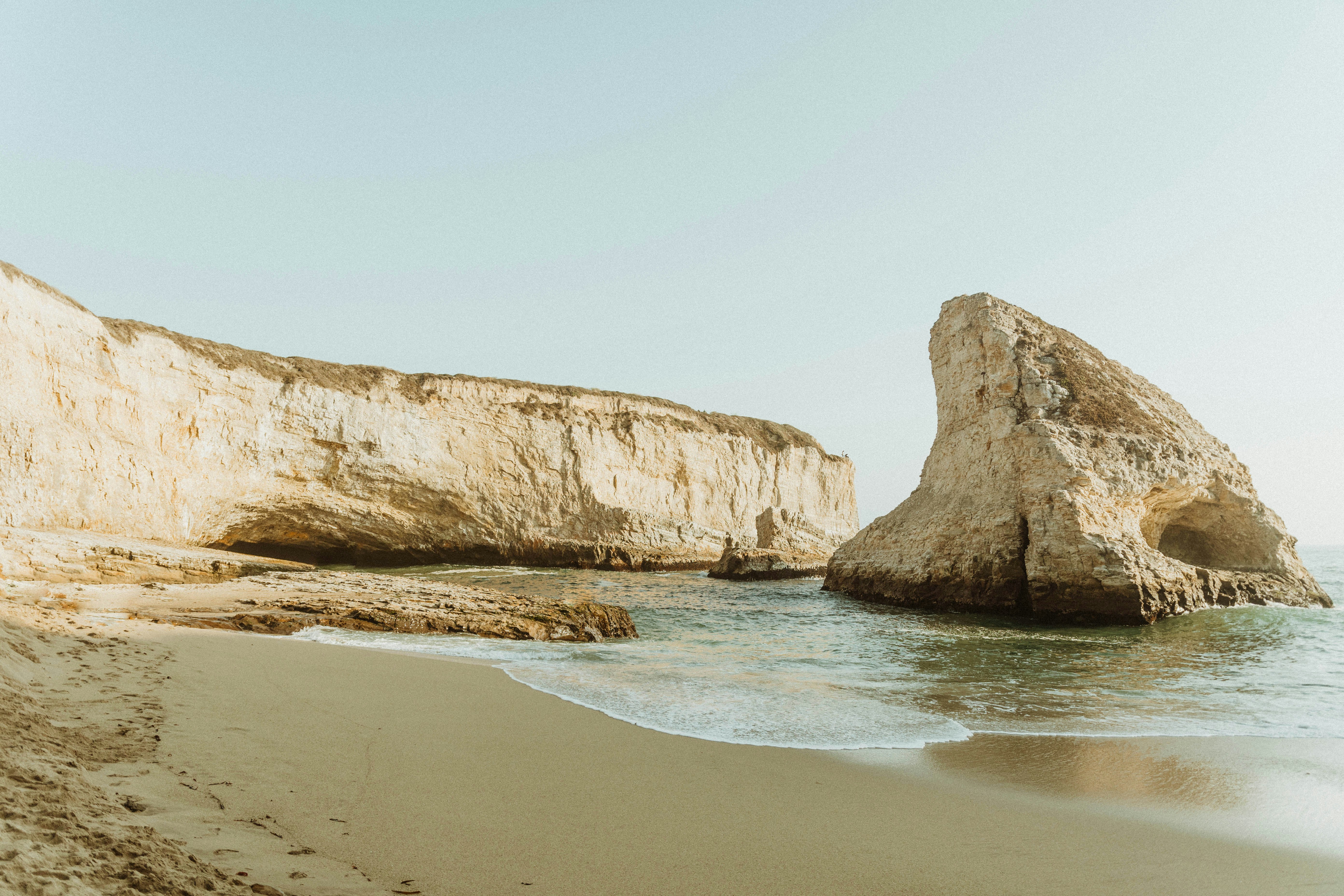 Coastal rock formations and calm sea under a clear sky.